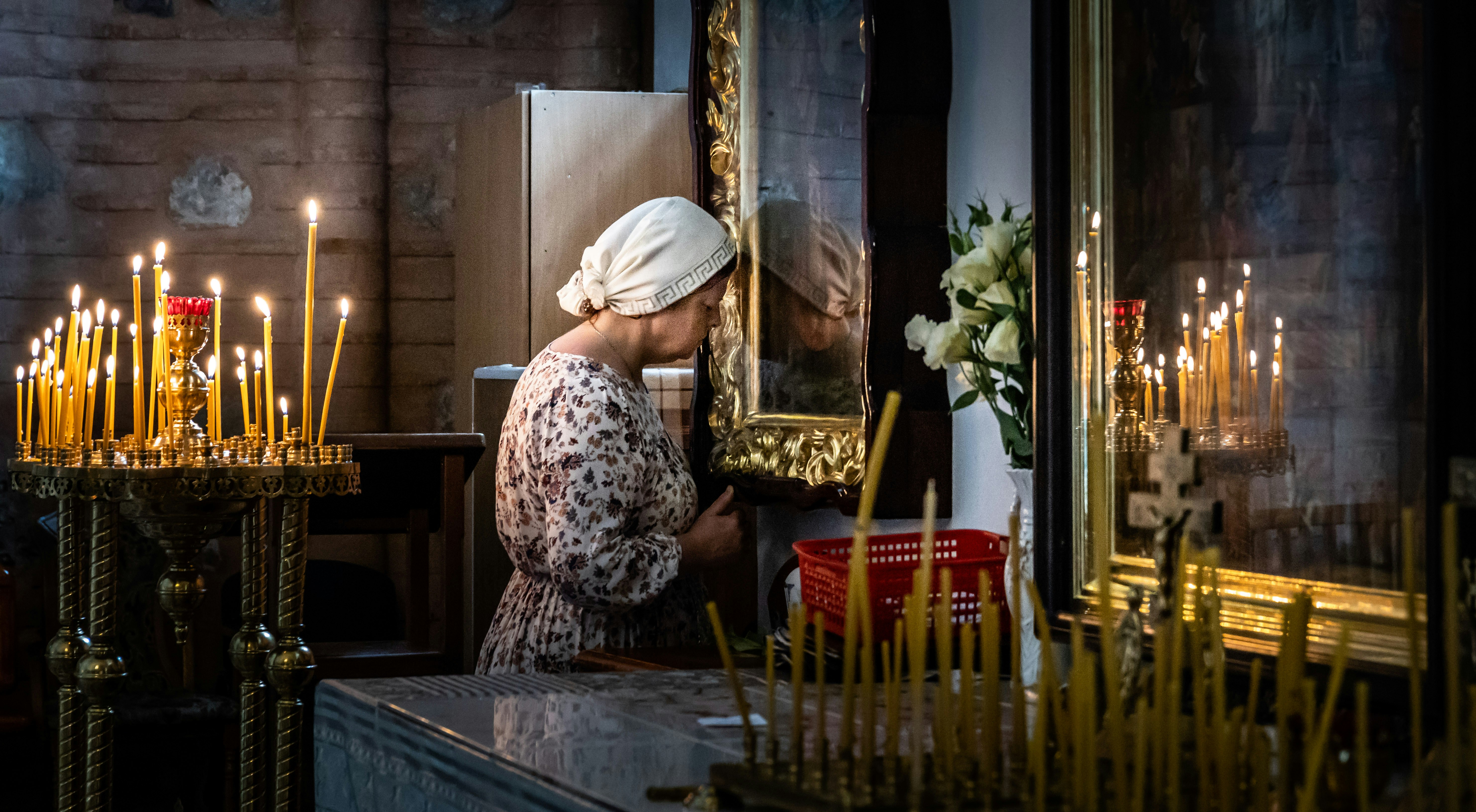 Quiet Communion: A Woman in White Headscarf at a Candlelit Icon Display