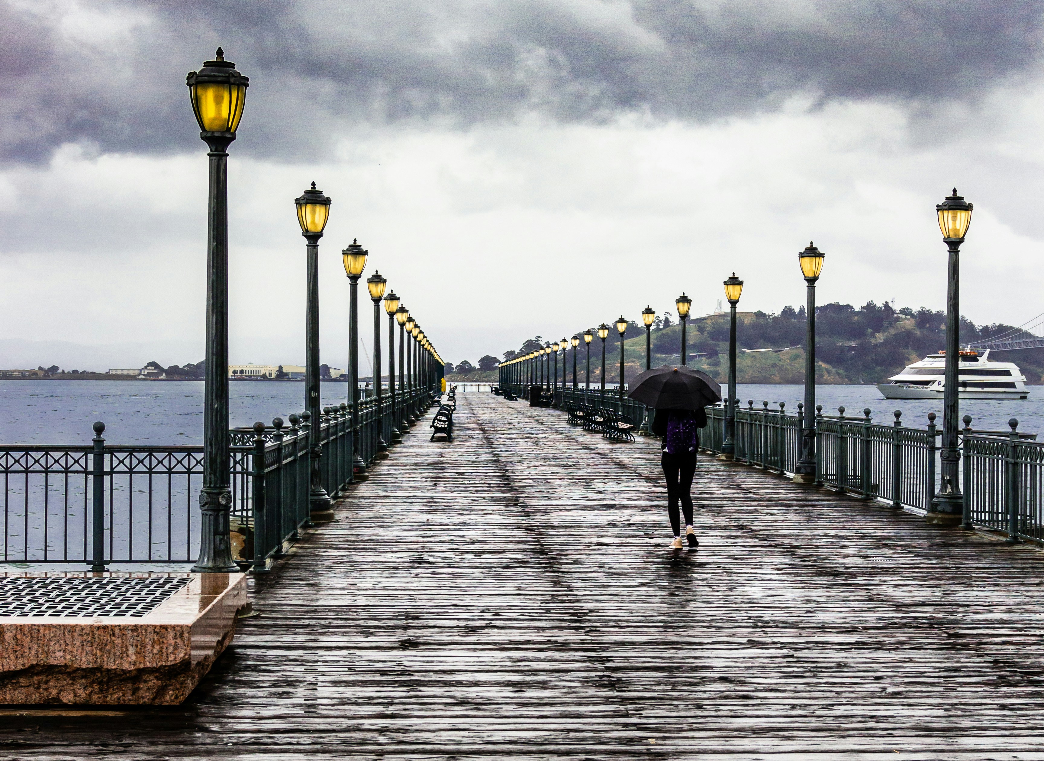 Rainy Promenade: A Lone Walker on the Glistening Pier