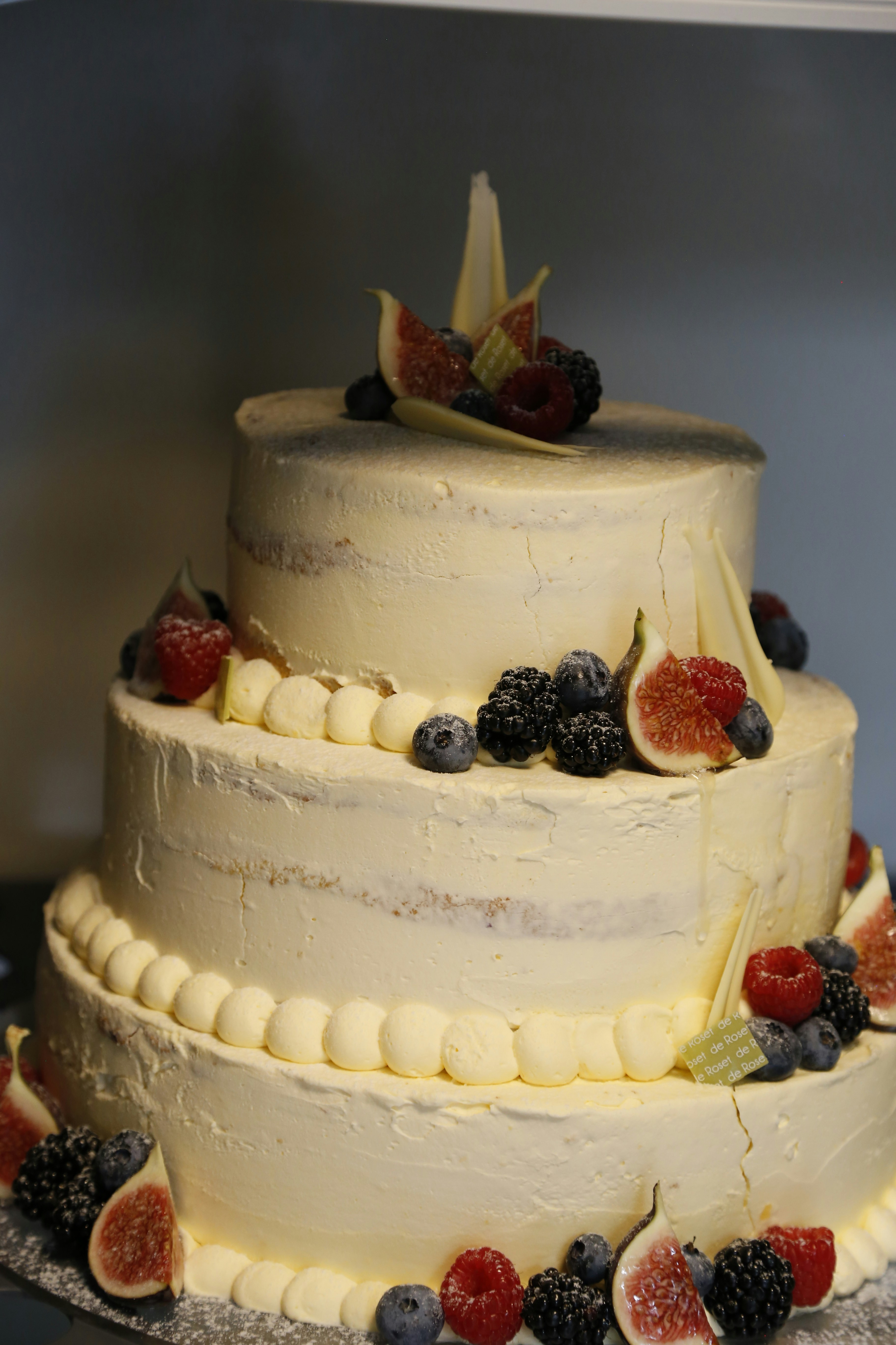 Tiered cream cake crowned with berries and fig shards