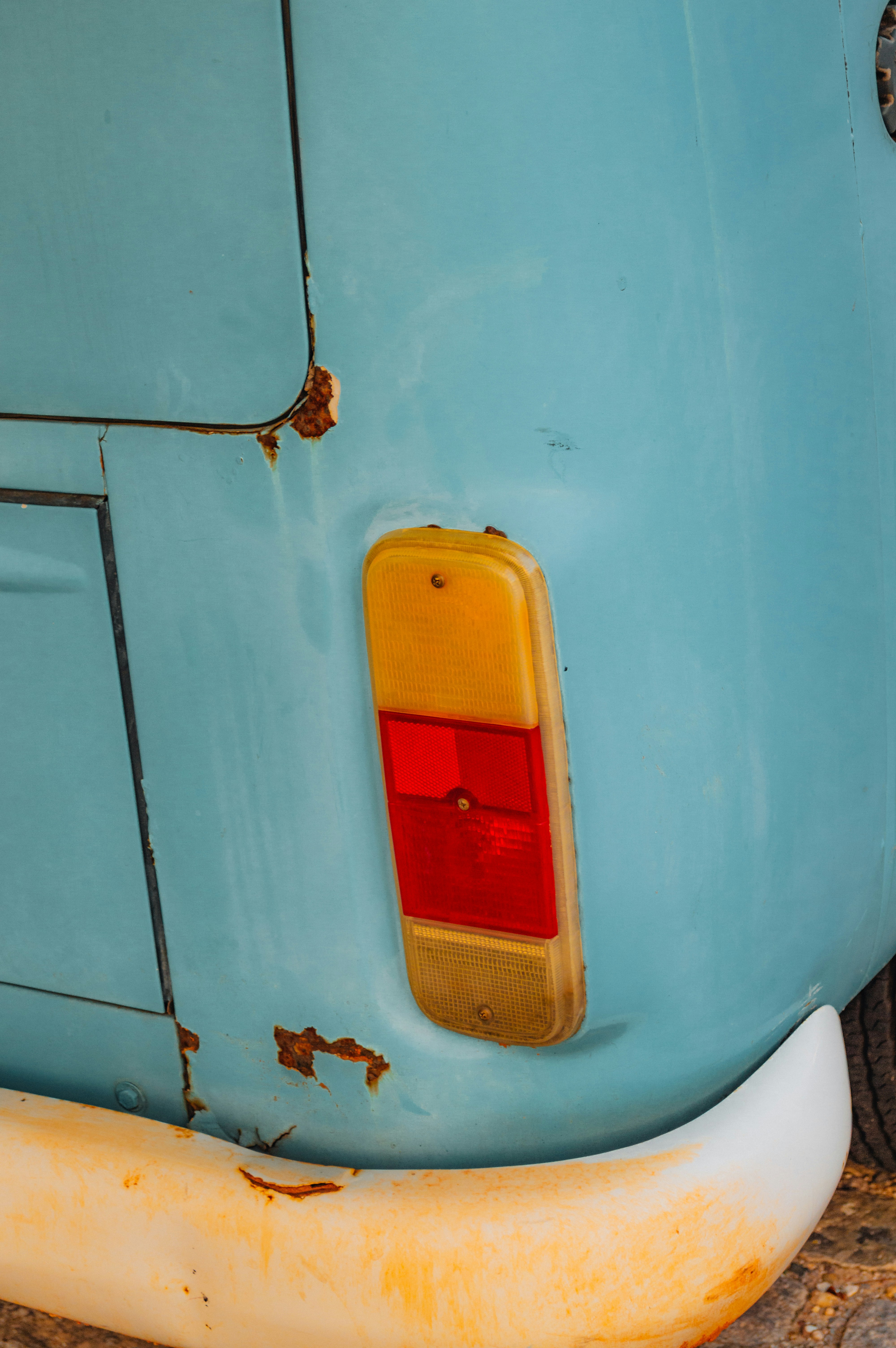 Rusted Blue Wake: The Tail Light and Curled Fender