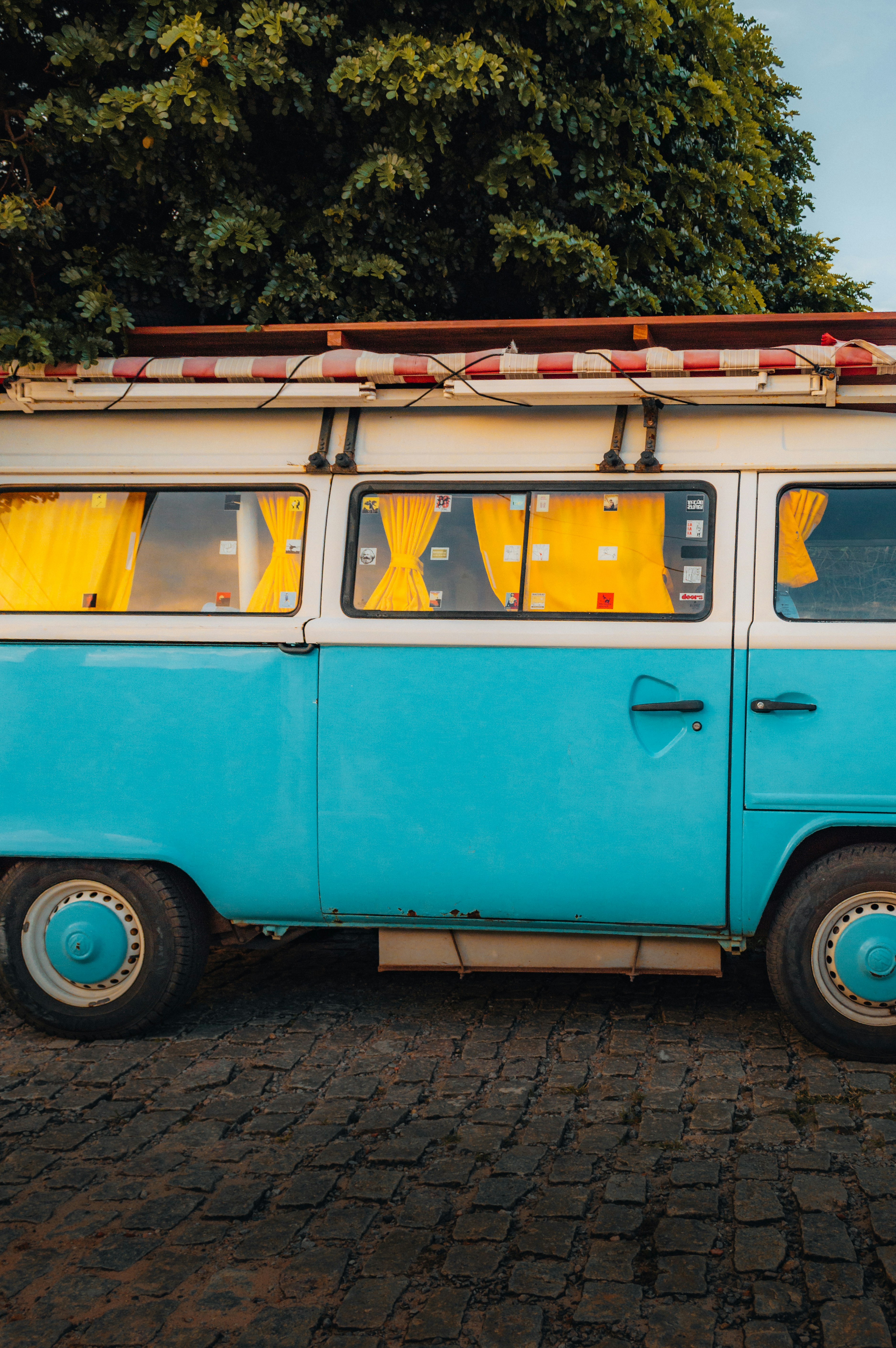 Blue and white vintage camper van with yellow curtains.