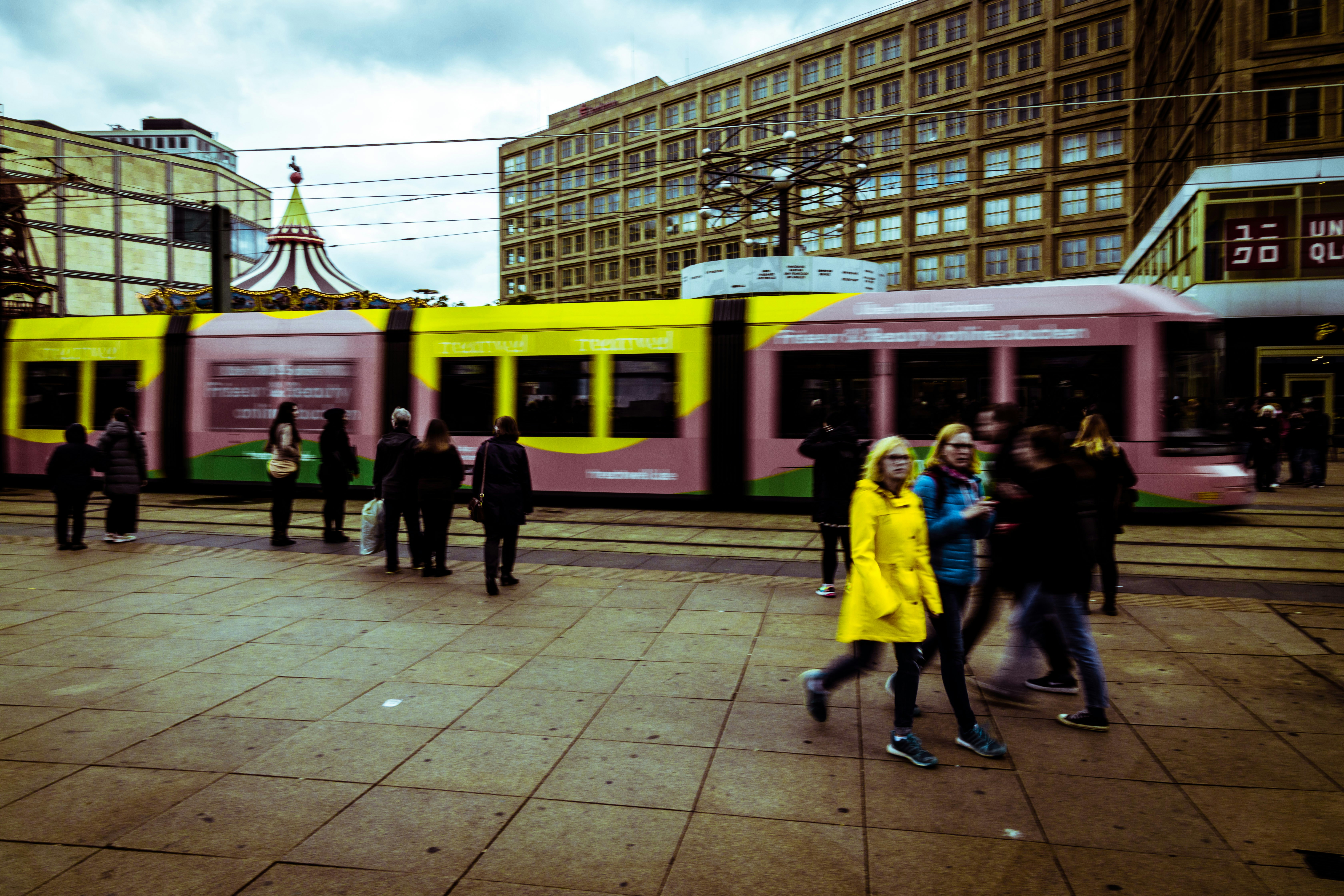 Yellow-Accent Tram Streaks Through a City Square as Pedestrians Pass
