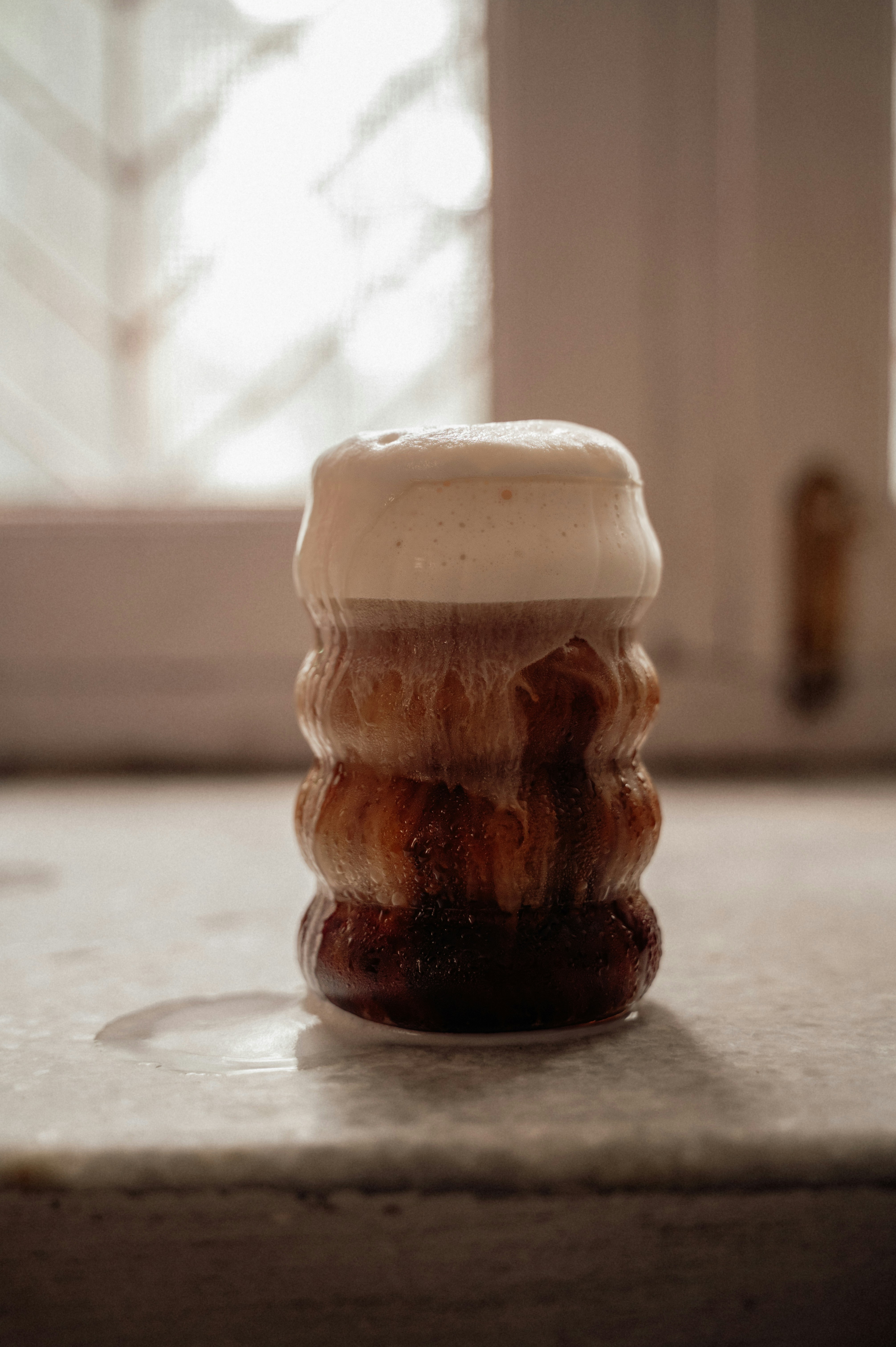 A Tilted Toast: A Foam-Crowned Beer Glass on a Quiet Kitchen Bar