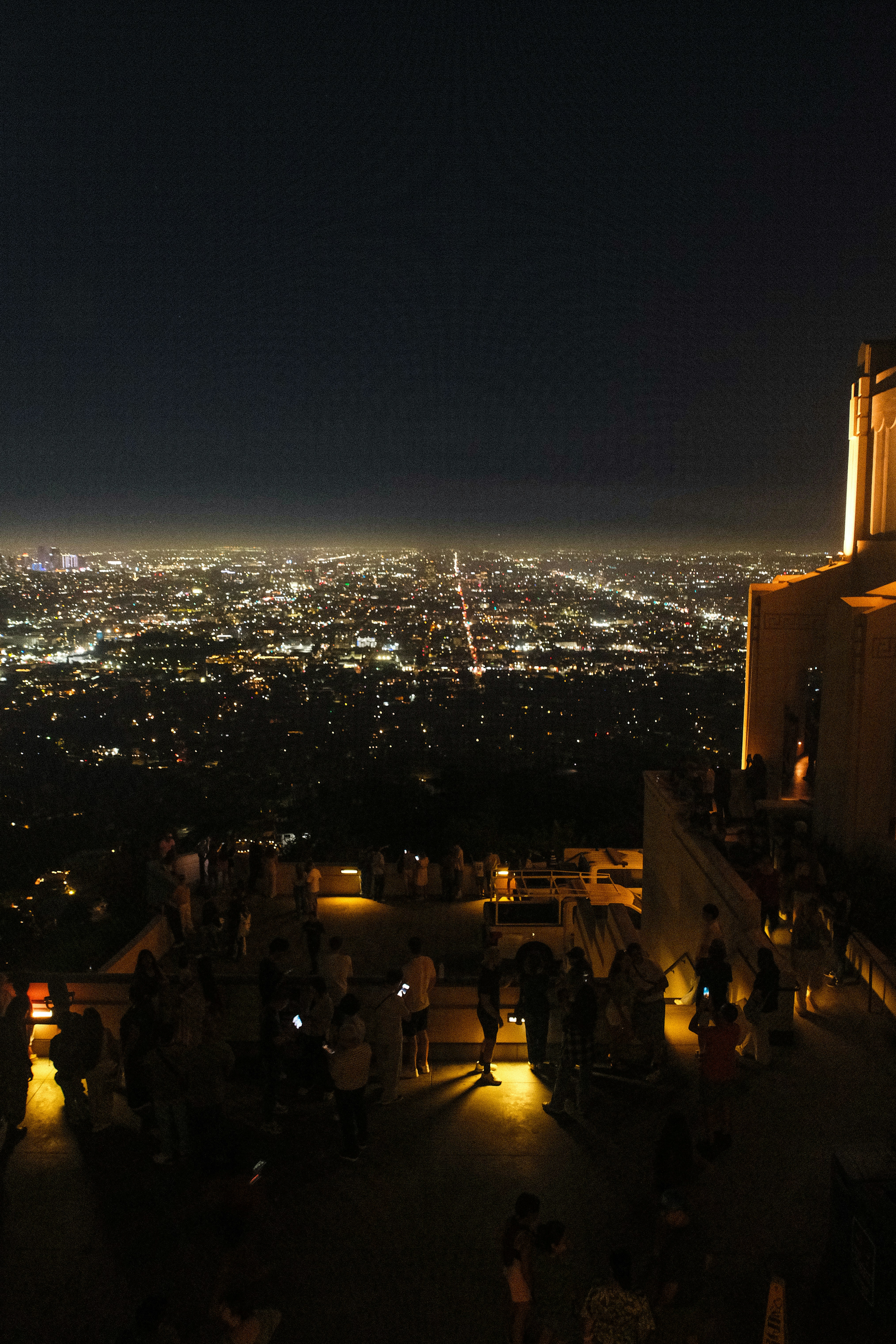 Night overlook from a hilltop with a glowing cityscape and warm terrace light