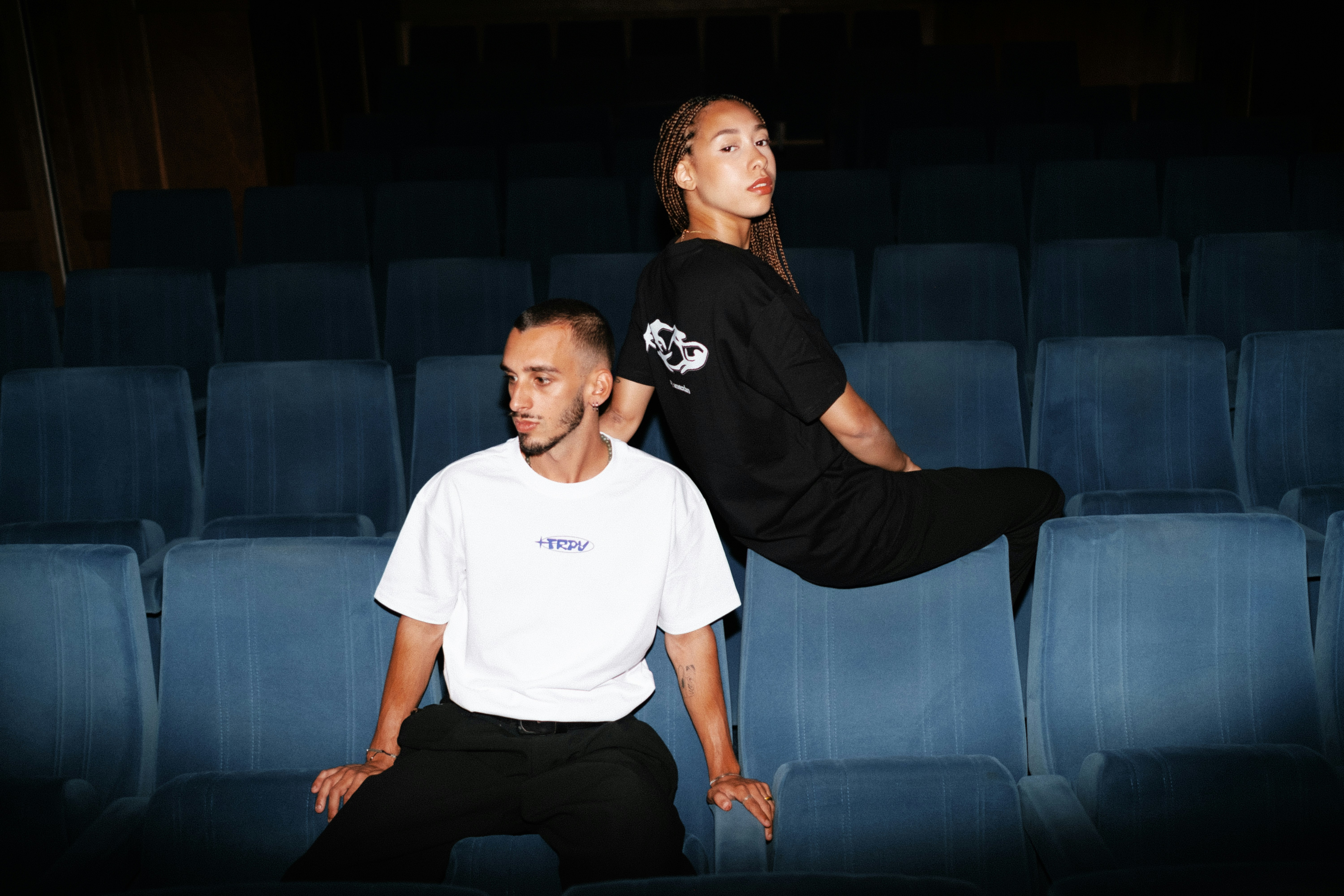 A Quiet Corner: Duo in Blue Row Poses within an Empty Theater