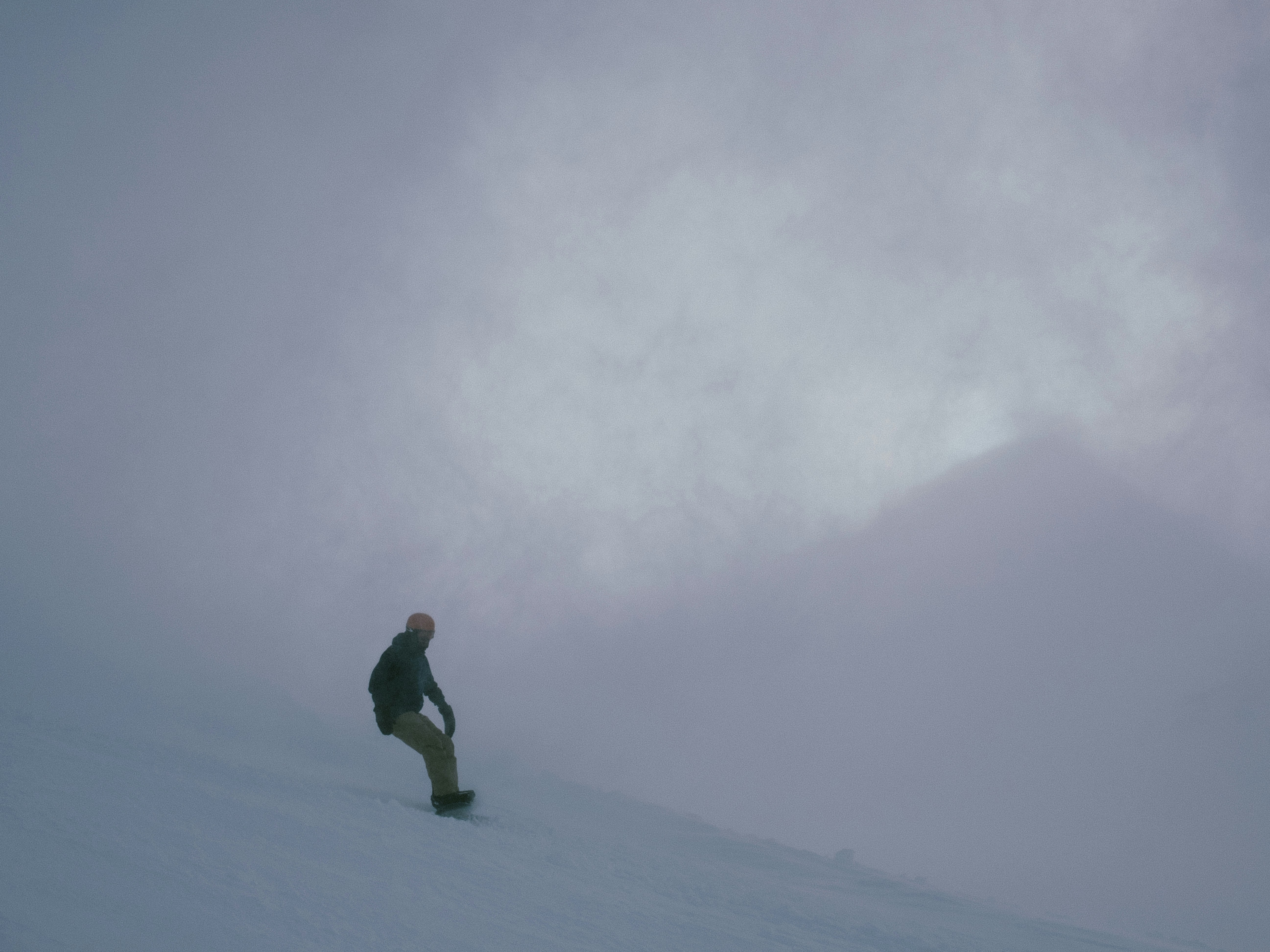 Snowbound Descent: A lone snowboarder carved through somber mist