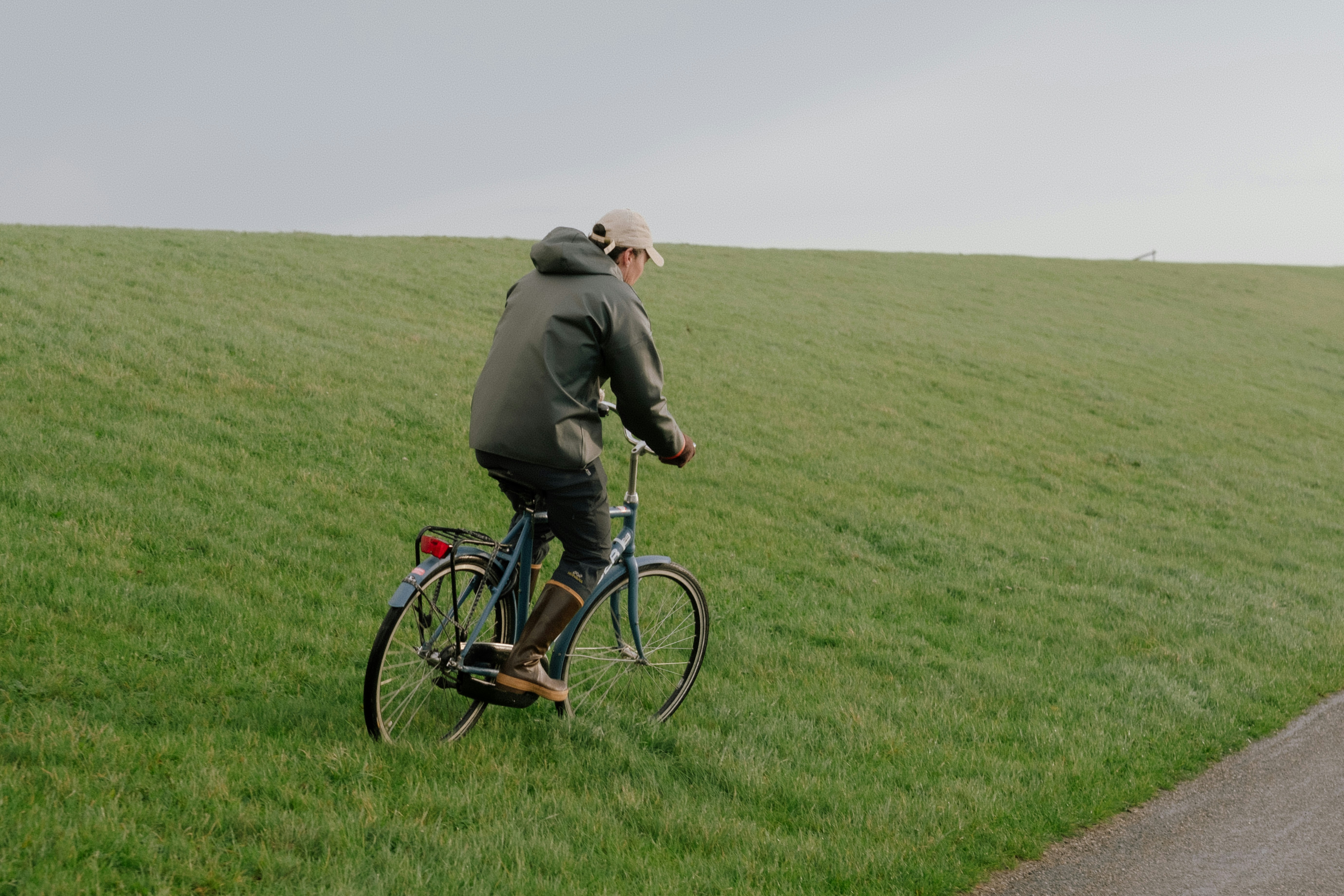 A lone cyclist ascends a grassy hill