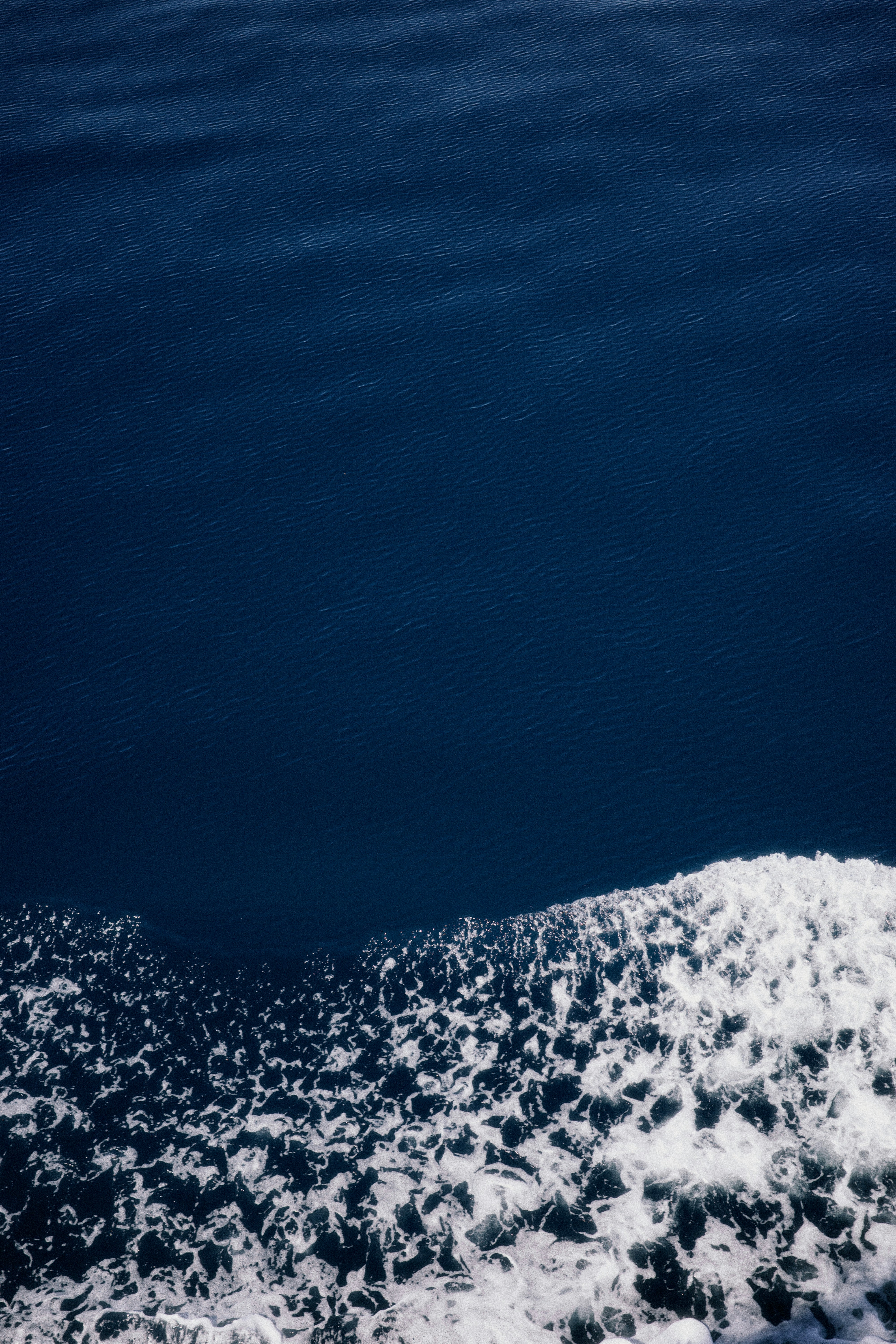 Surfacing Edge: A Deep Blue Wake Rolls Into Quiet Gravity