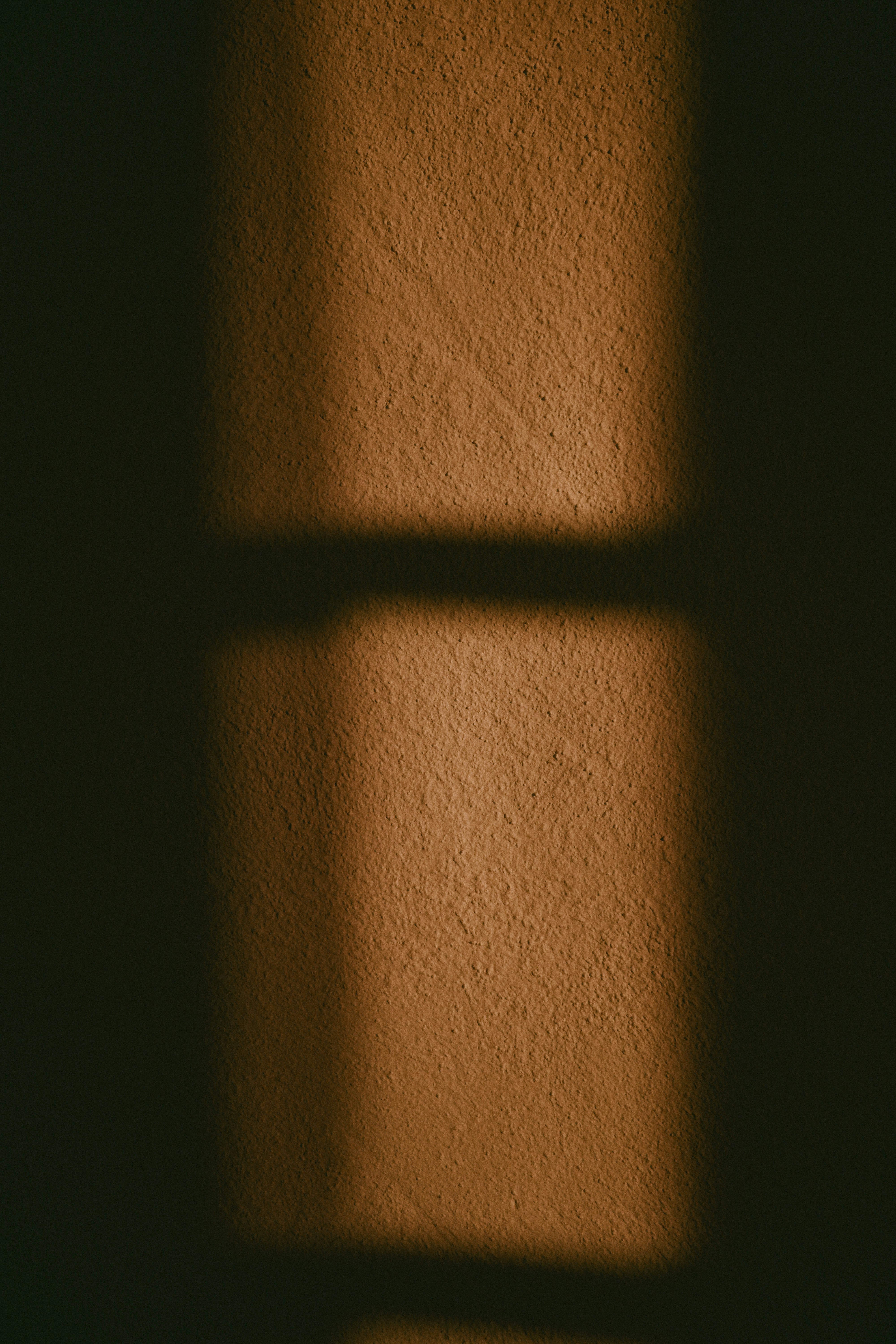 Warm window-gap shadows: a vertical glow through textured wall panes