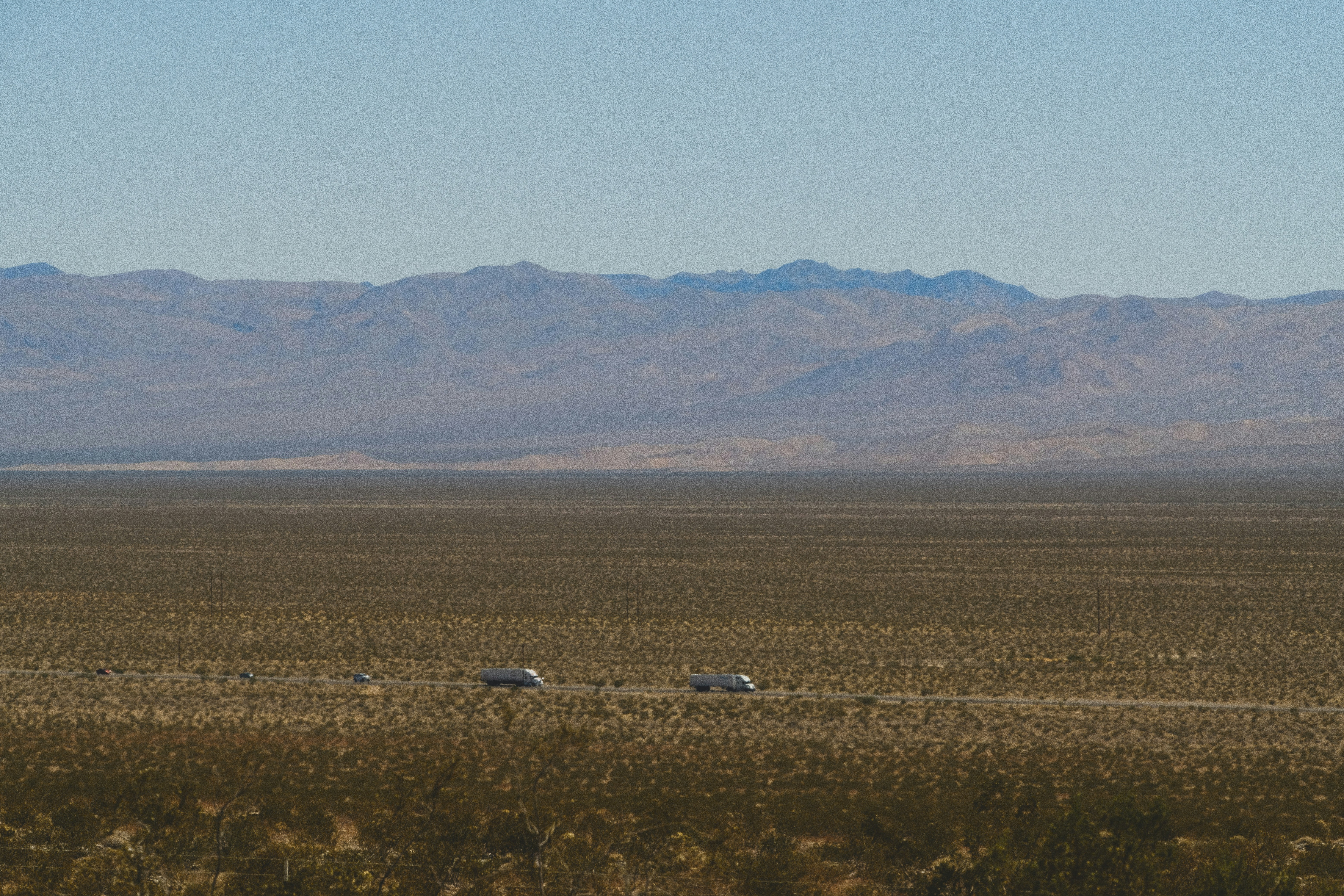 Desert Track: Distant Mountains and Moving Cars on an Arid Plain