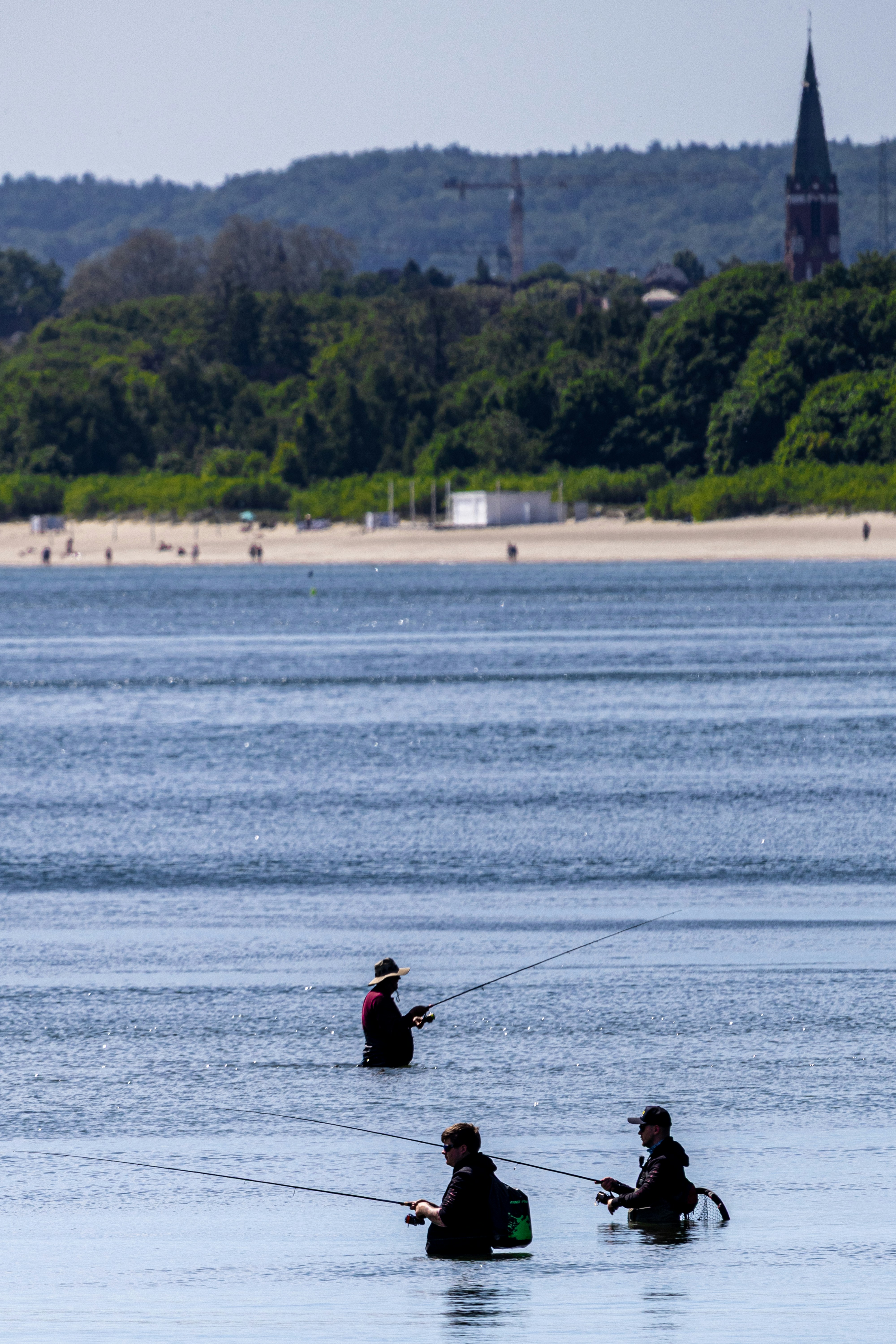 Riverside Anglers: Calm Focus Beneath a Towering Skyline