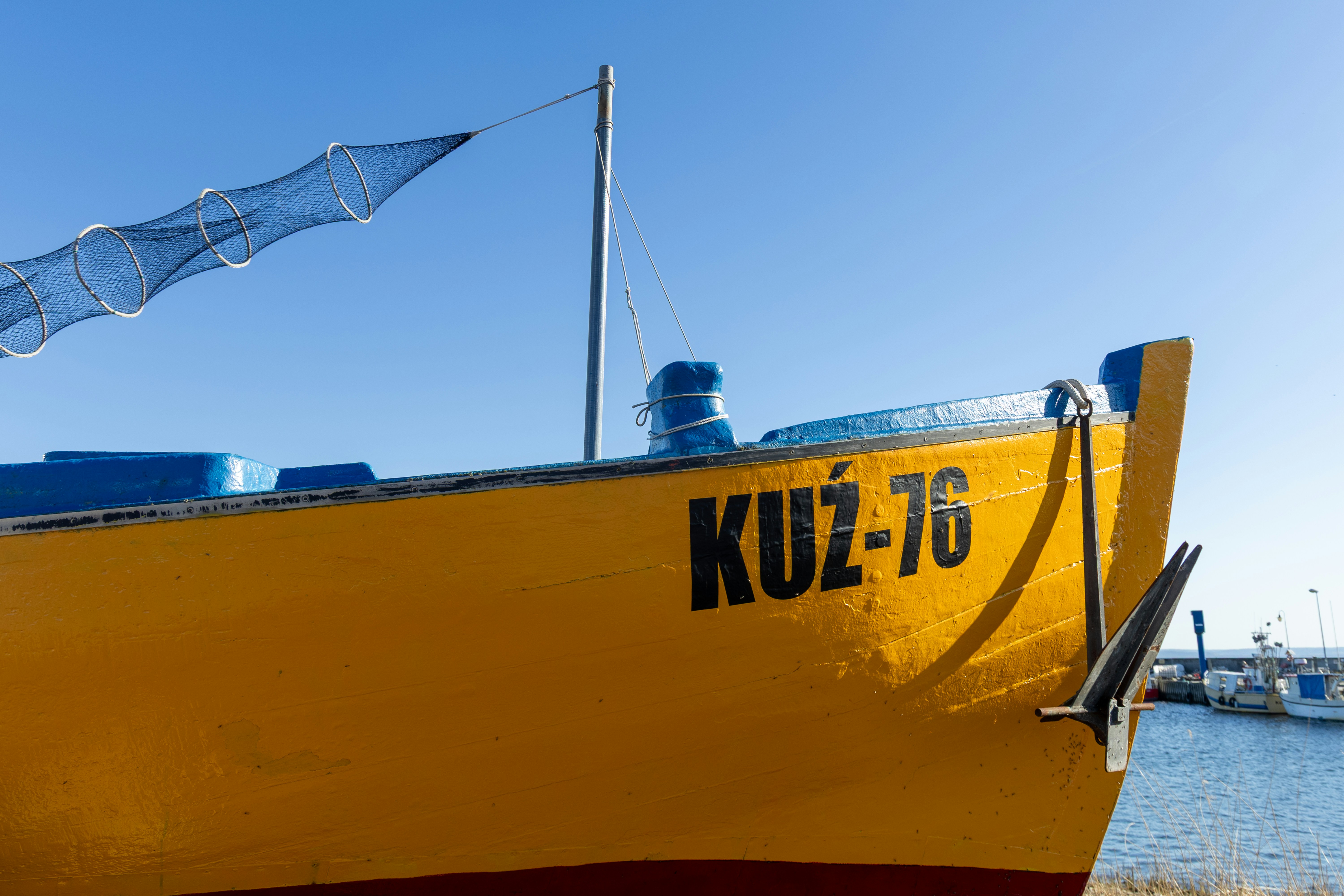 Yellow Hull at the Dock: KUZ-76 Against a Clear Maritime Sky