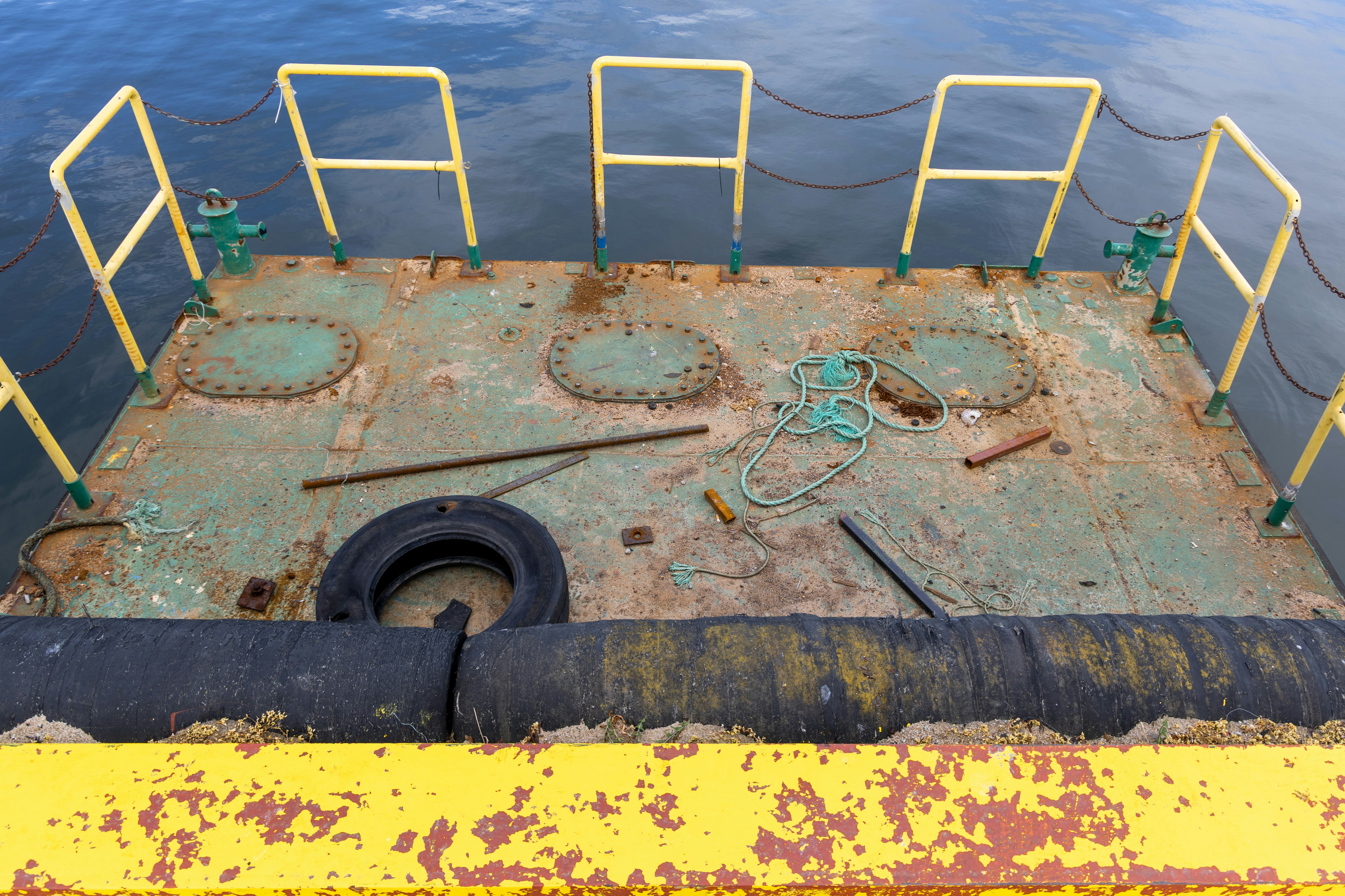 Weathered Dock Deck with Rusted Hatch and Coiled Rope