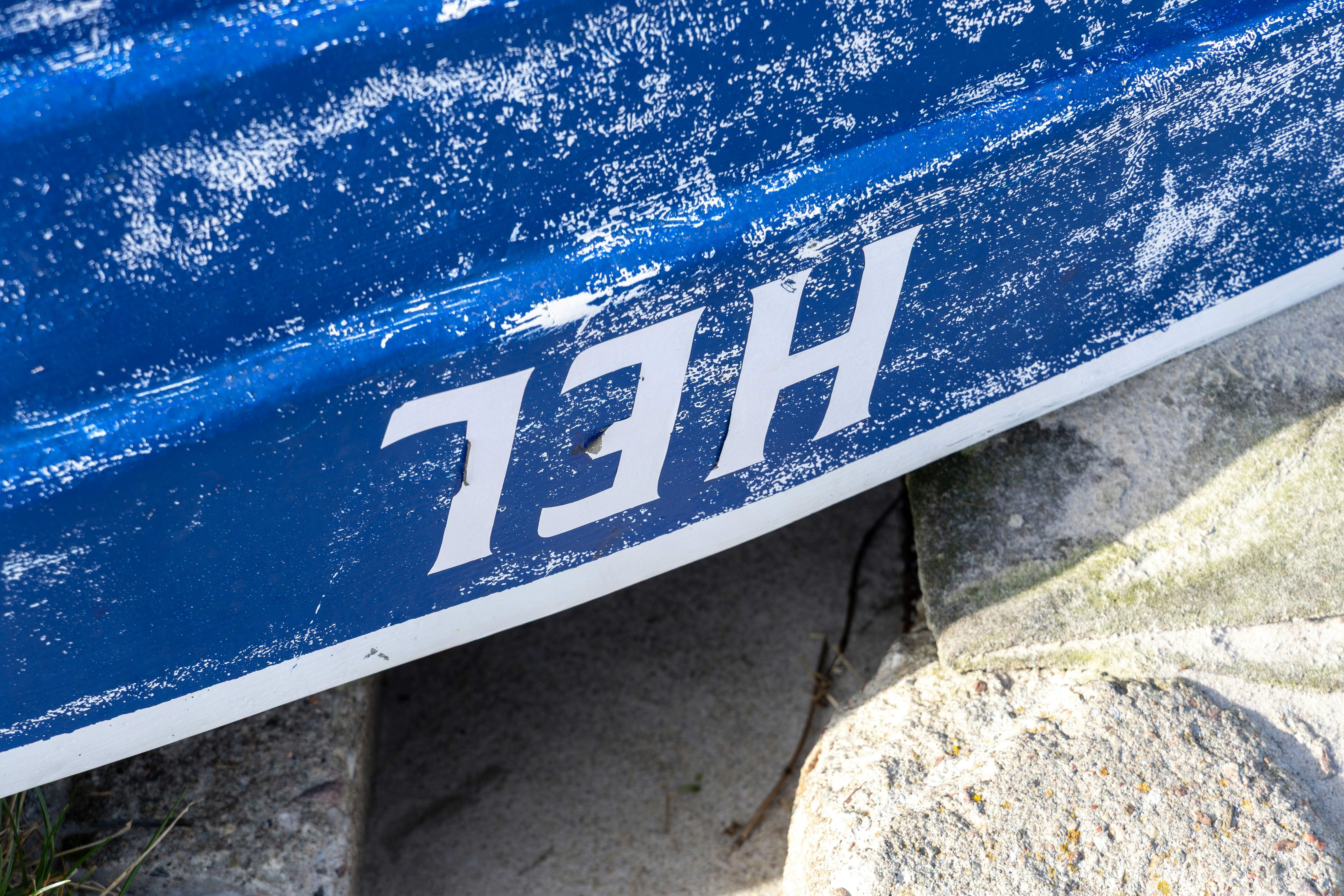 Blue Weathered Hull with White HEL Logo Leaning on Sand