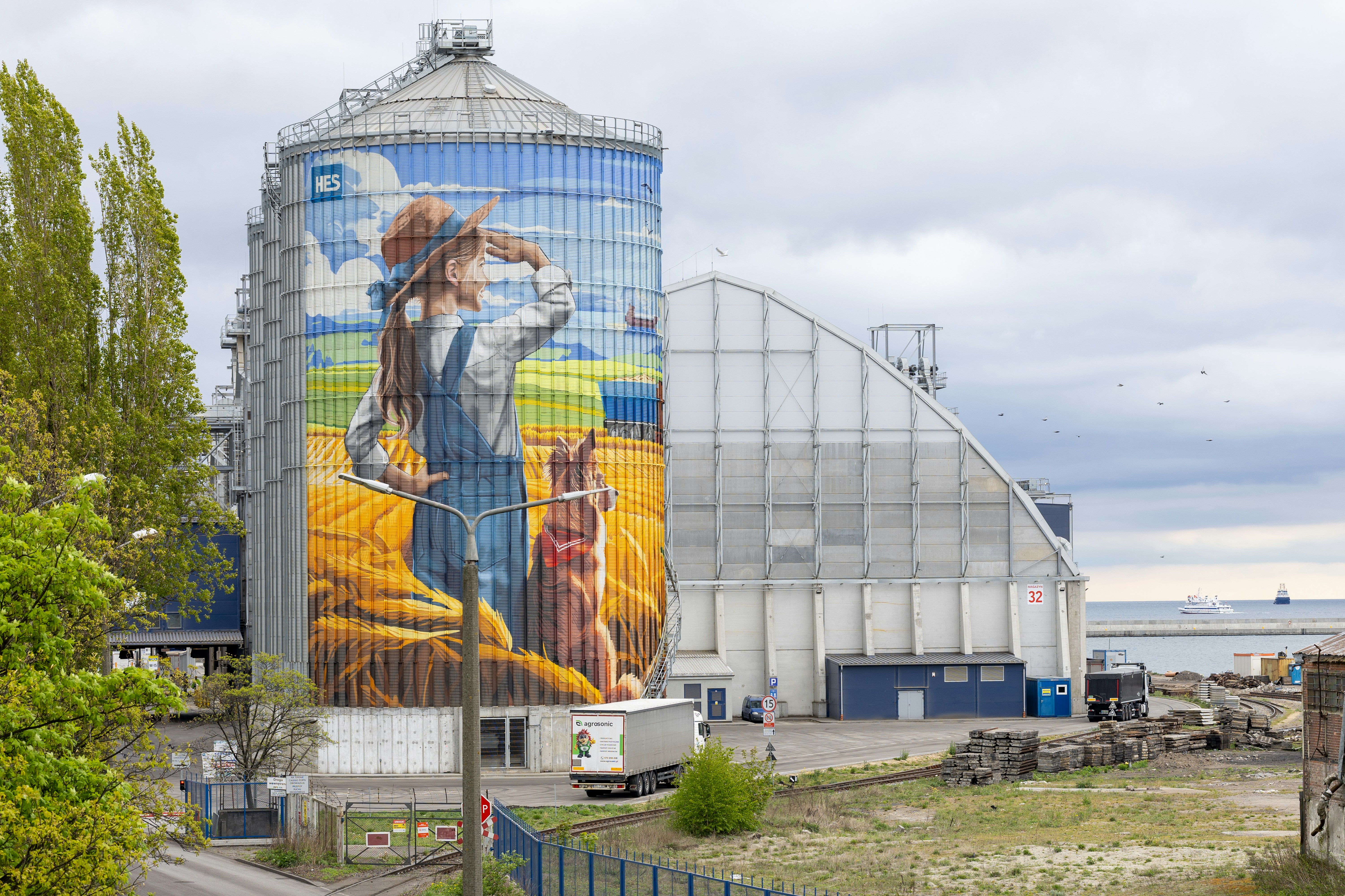 Muraled Grain Silo Anchored by Waterfront Looms