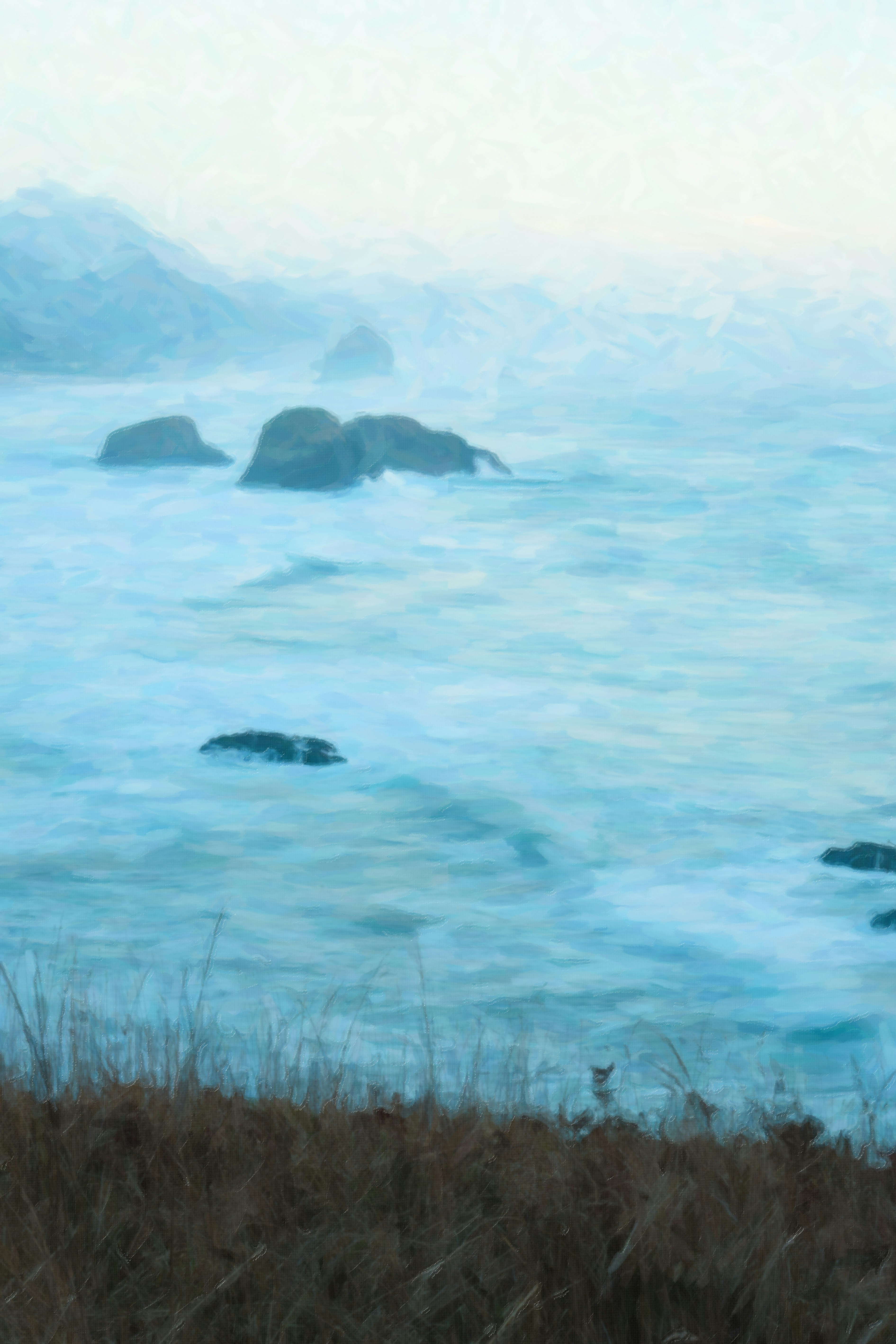 Mist over blue tides: rocks emerging from a tranquil shore