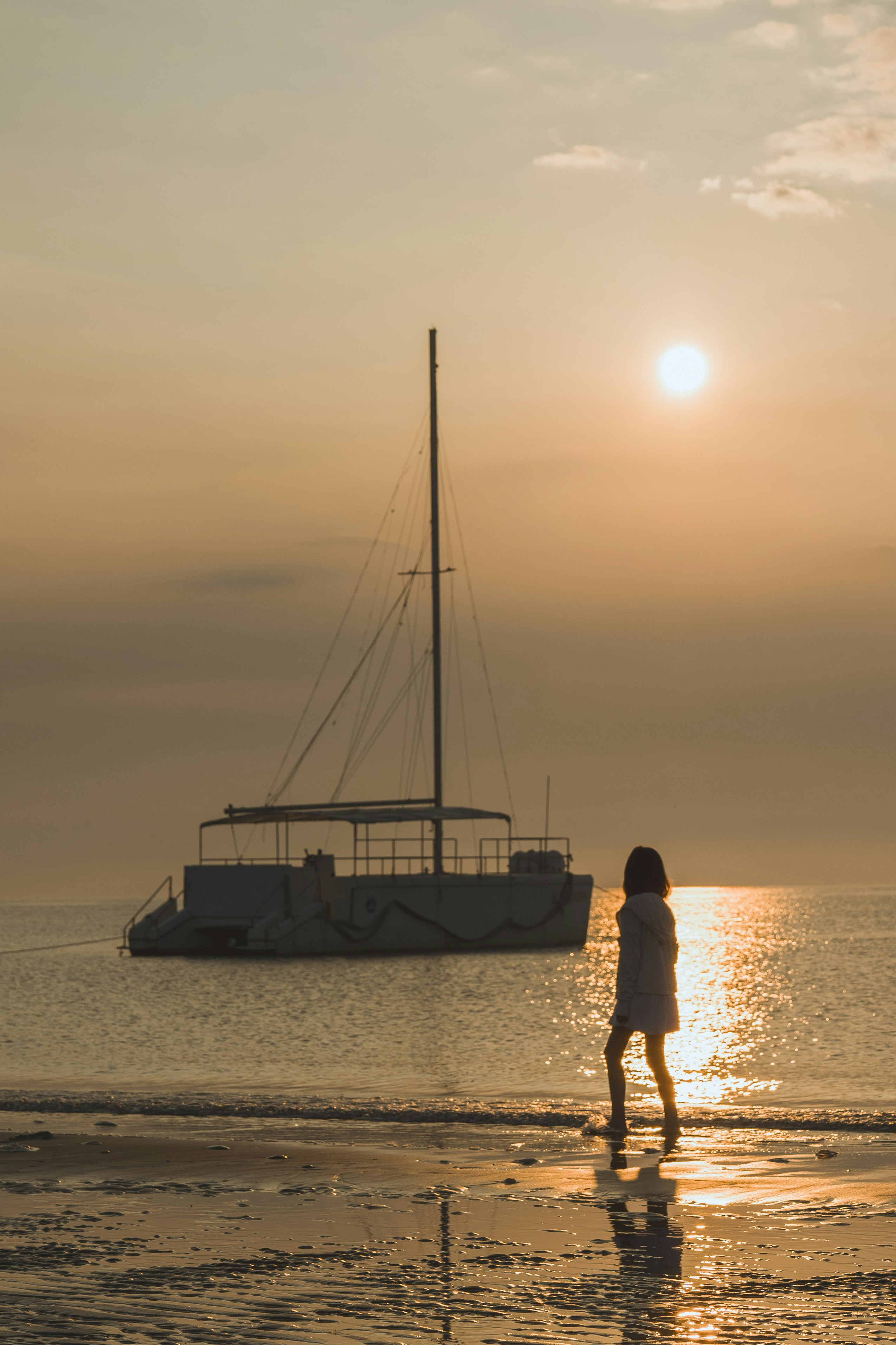 Silhouette at Sunset: A Quiet Moment by the Sailboat
