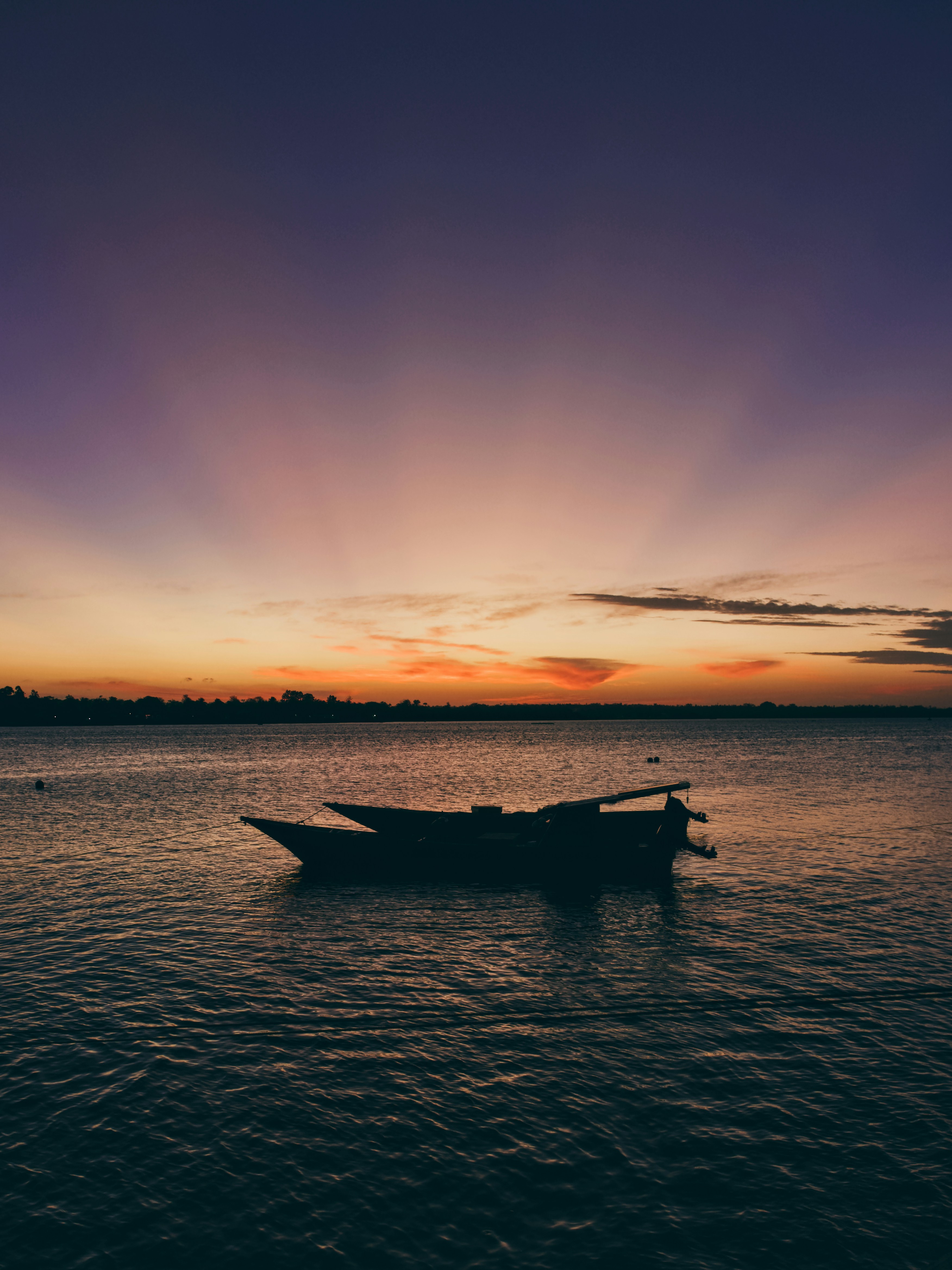 Sunset Silhouette: A lone boat drifting on tranquil waters
