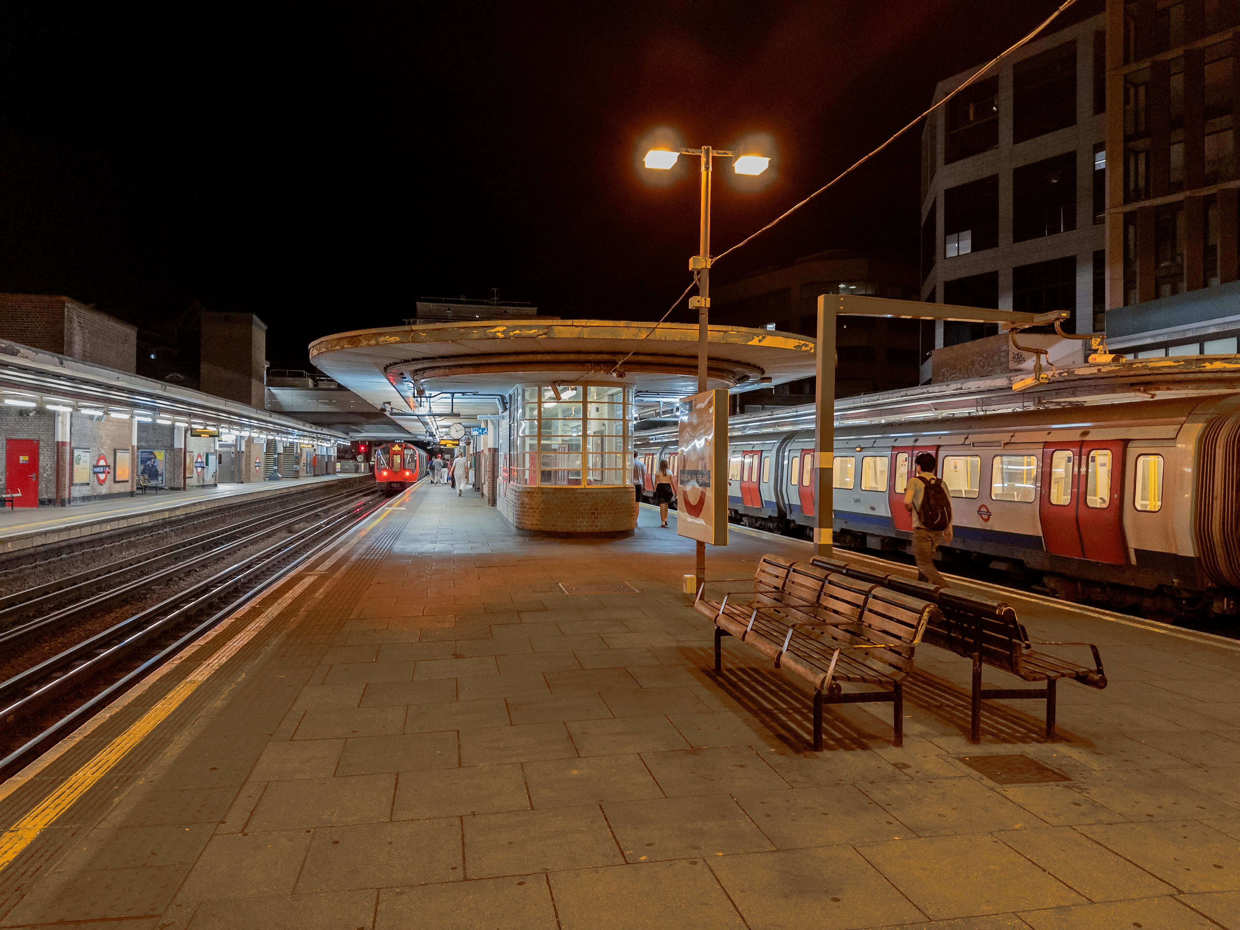 Night at the Platform: Warm Lights, Empty Benches, Moving Trains