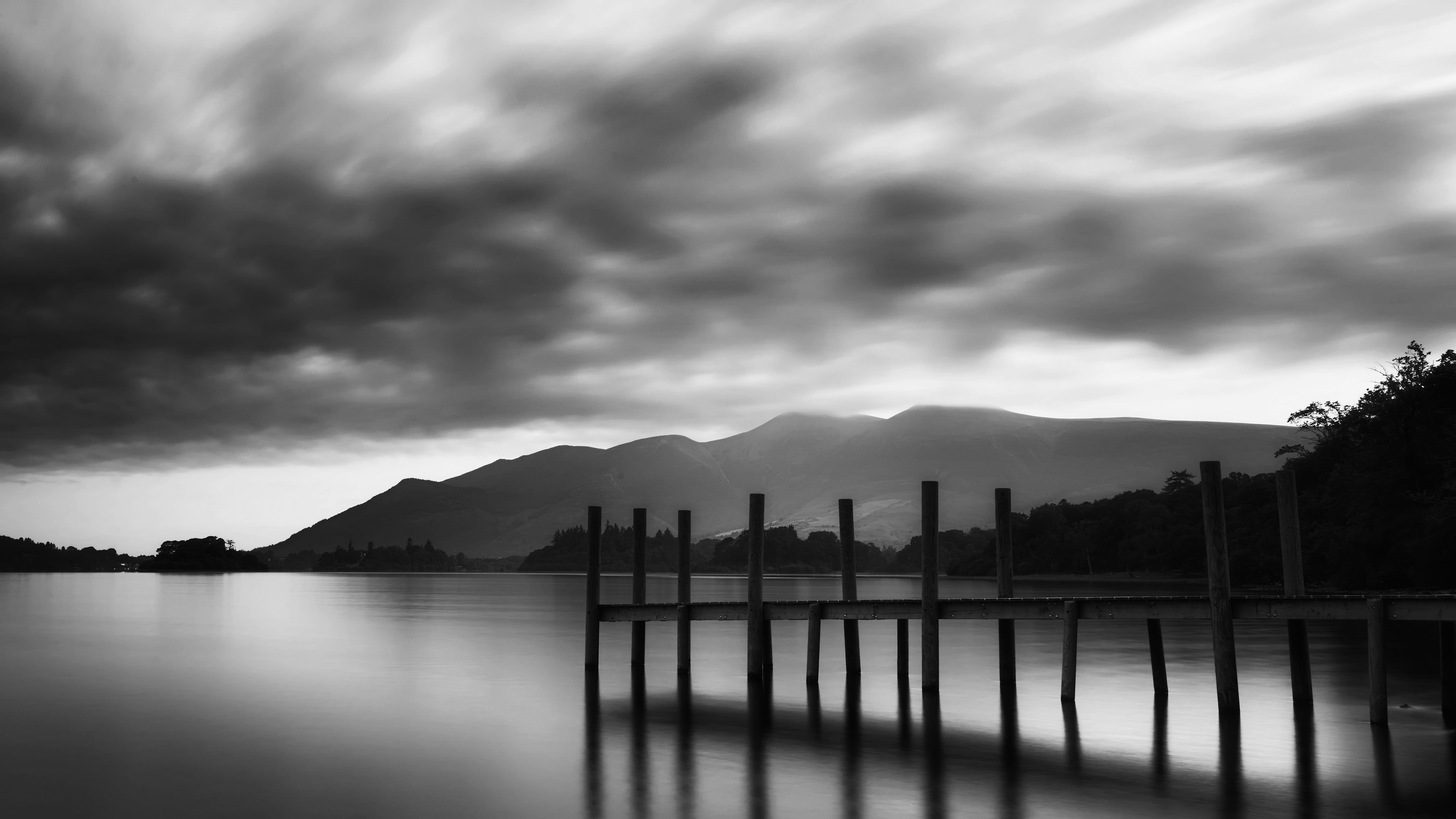 Silhouetted jetty Stills: Calm Lake Under Rolling Clouds