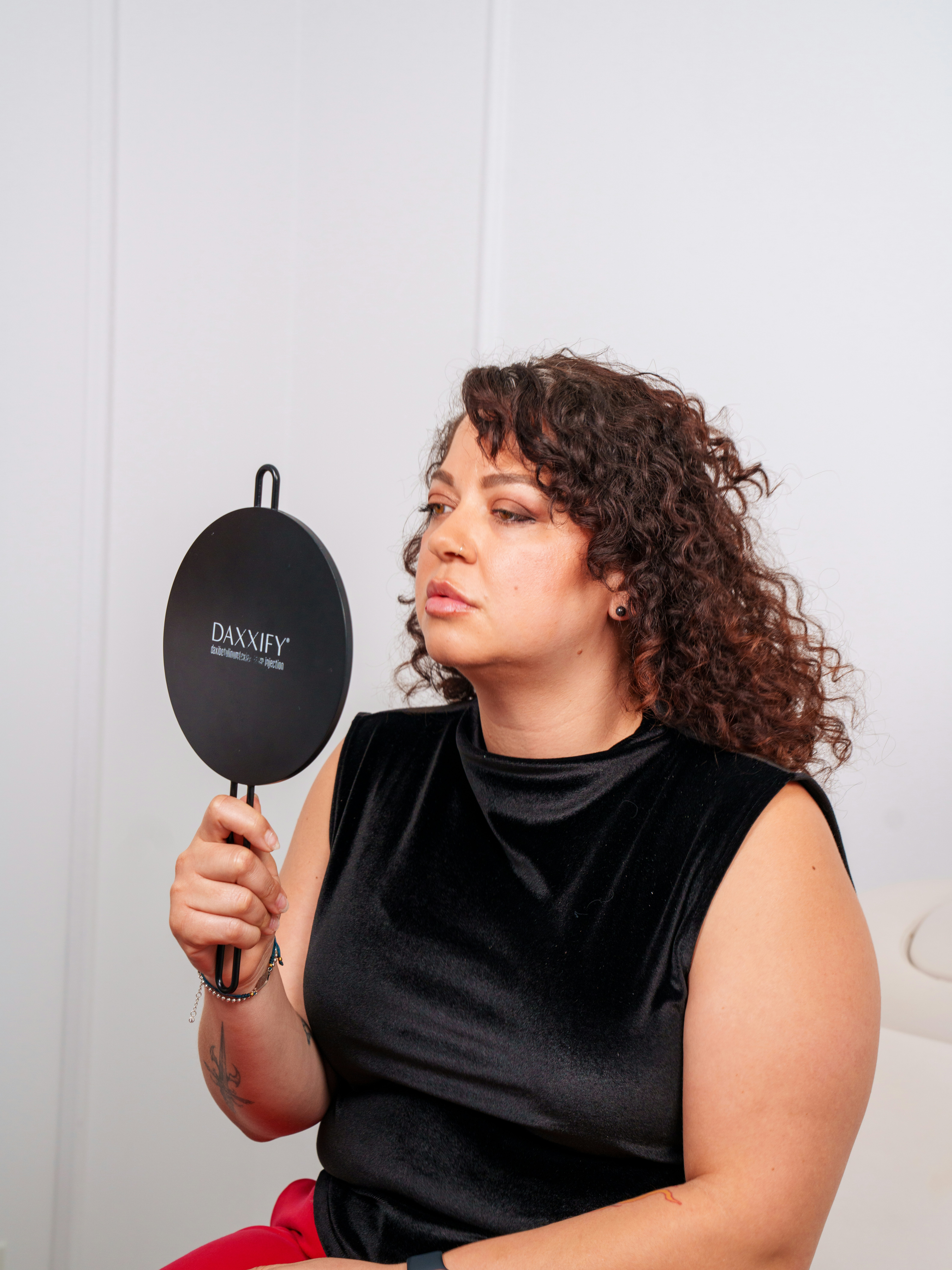 Portrait of a focused reflection: woman with handheld mirror in a minimalist room