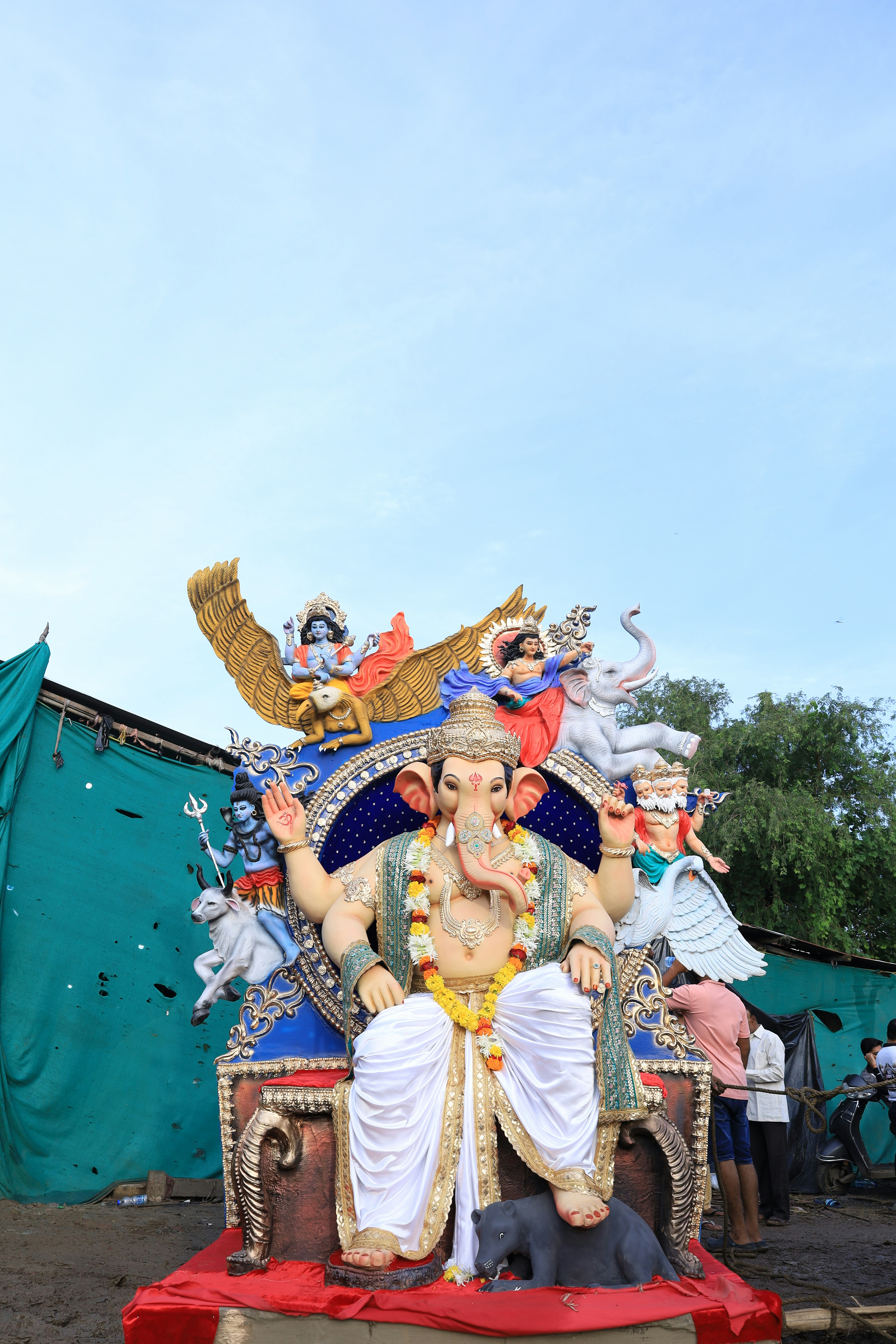 Gilded Ganesh on a ceremonial pedestal under a blue sky