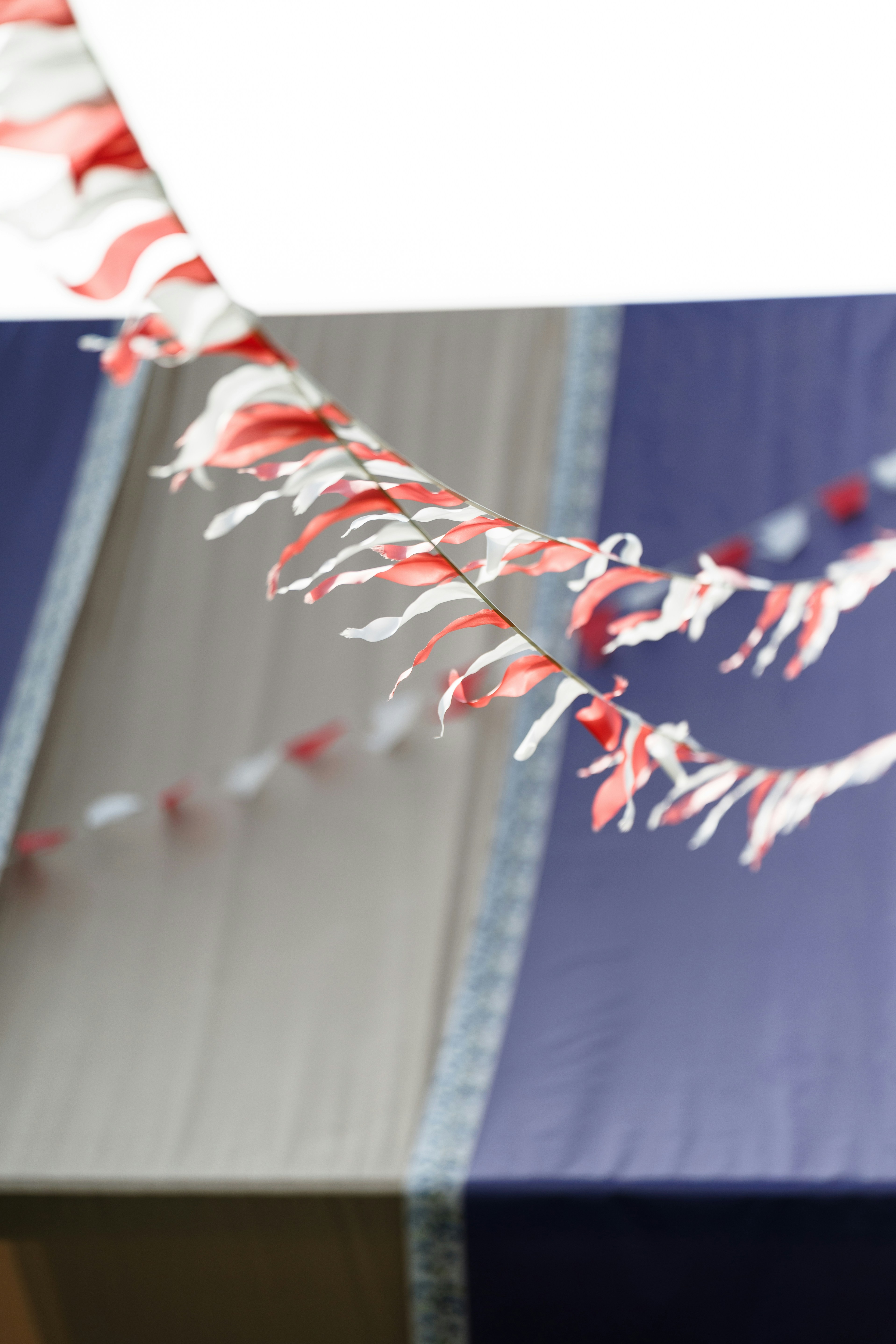 Threaded Lines: Red and White Banners across a Blue Facade