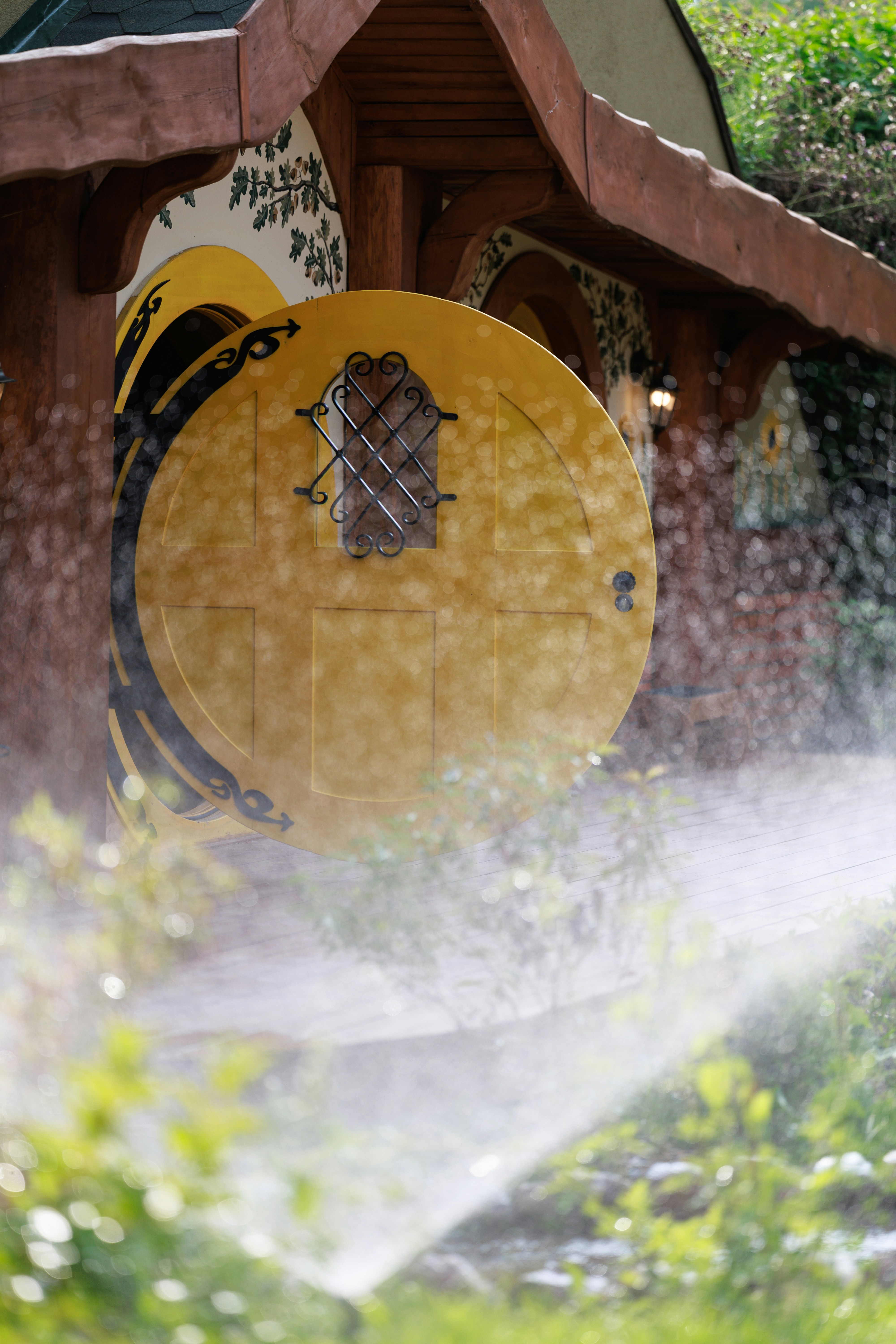 Yellow Round Door with Decorative Grille Amid a Garden Water spray