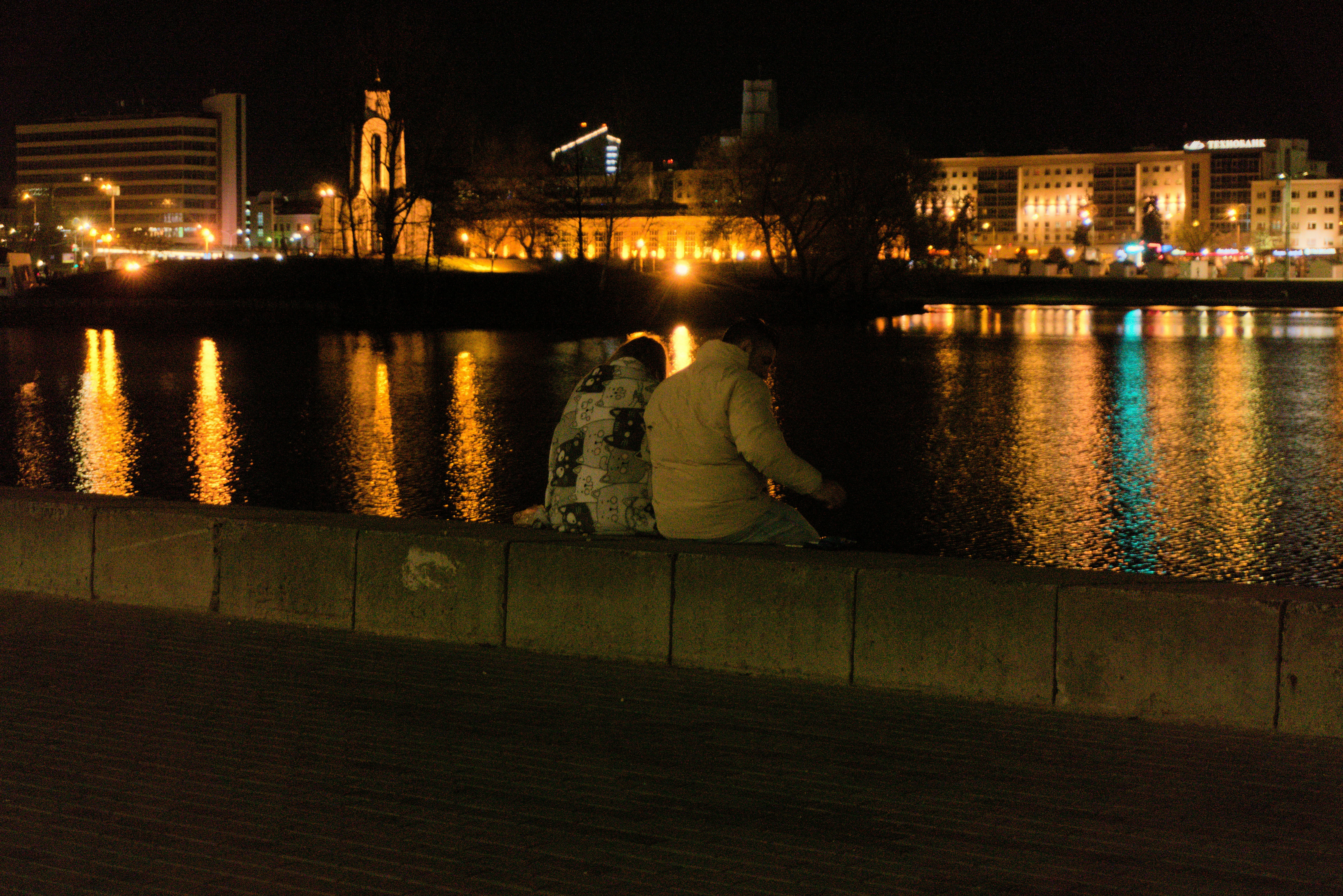 Night Chat by the River: Two Silhouettes Under City Lights