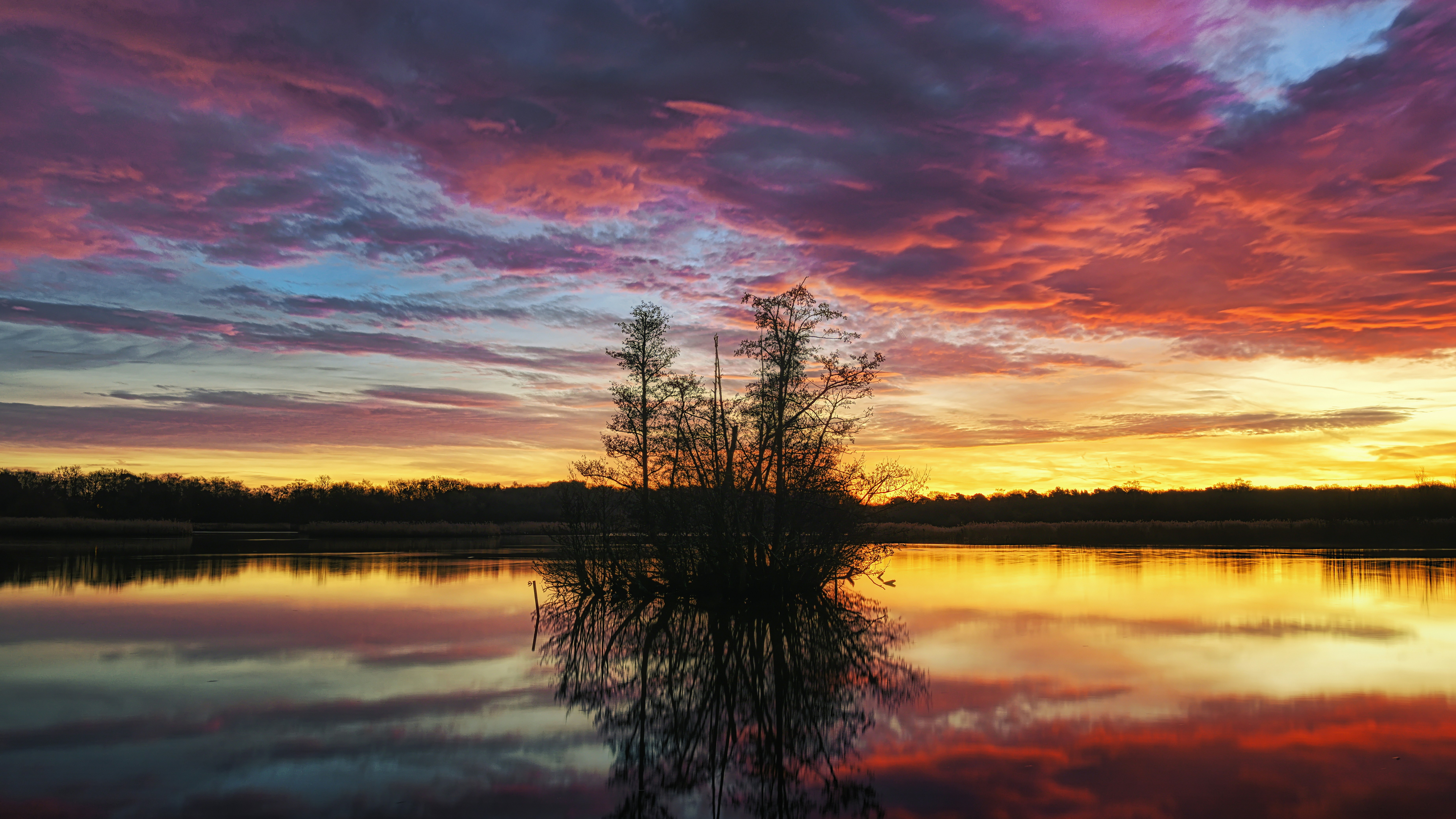 Twin silhouettes at dusk: a tranquil island in a molten sky