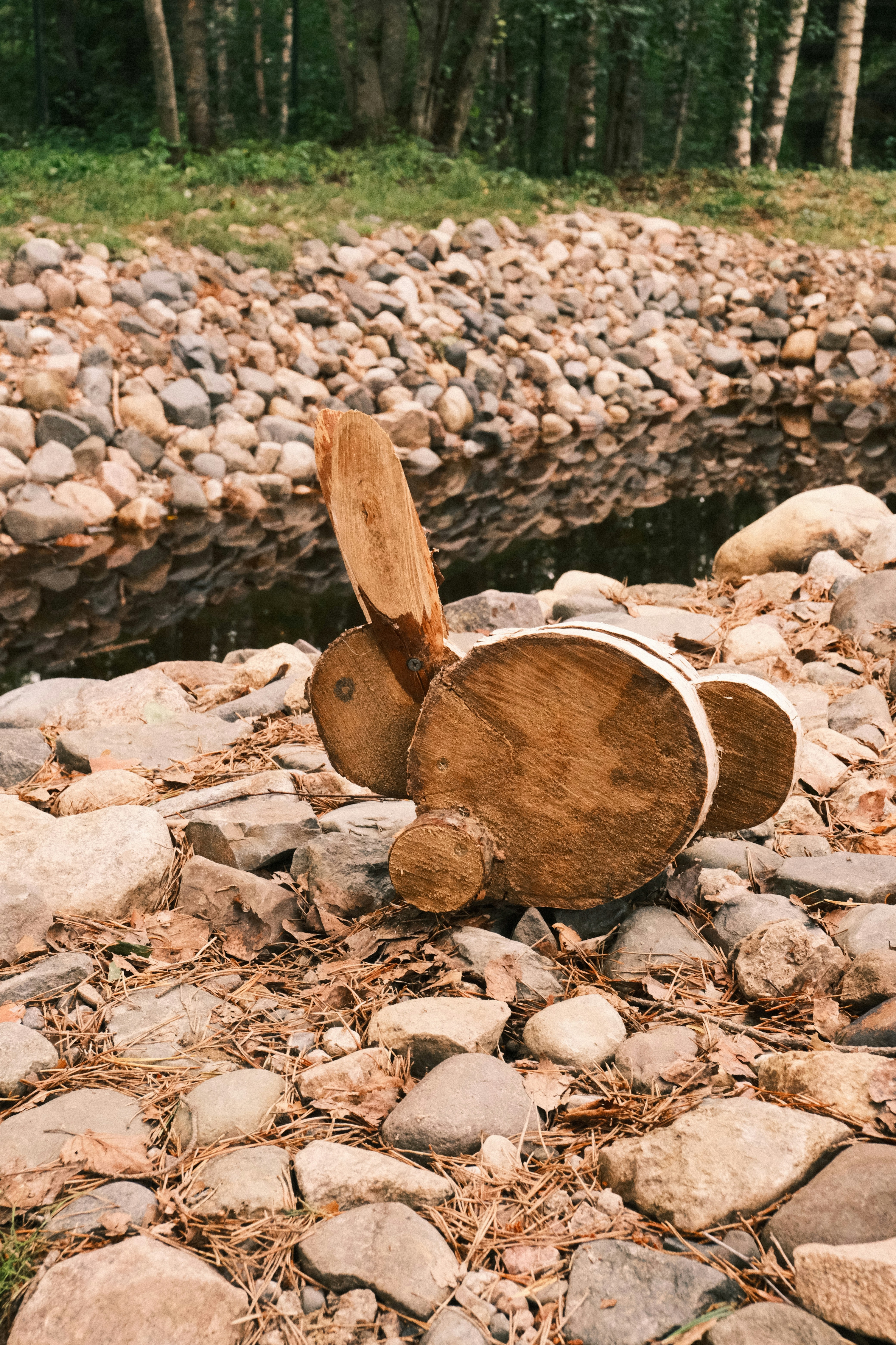 Alcove of Wood: A Pebble Ground Scene with a Weathered Log Sculpture