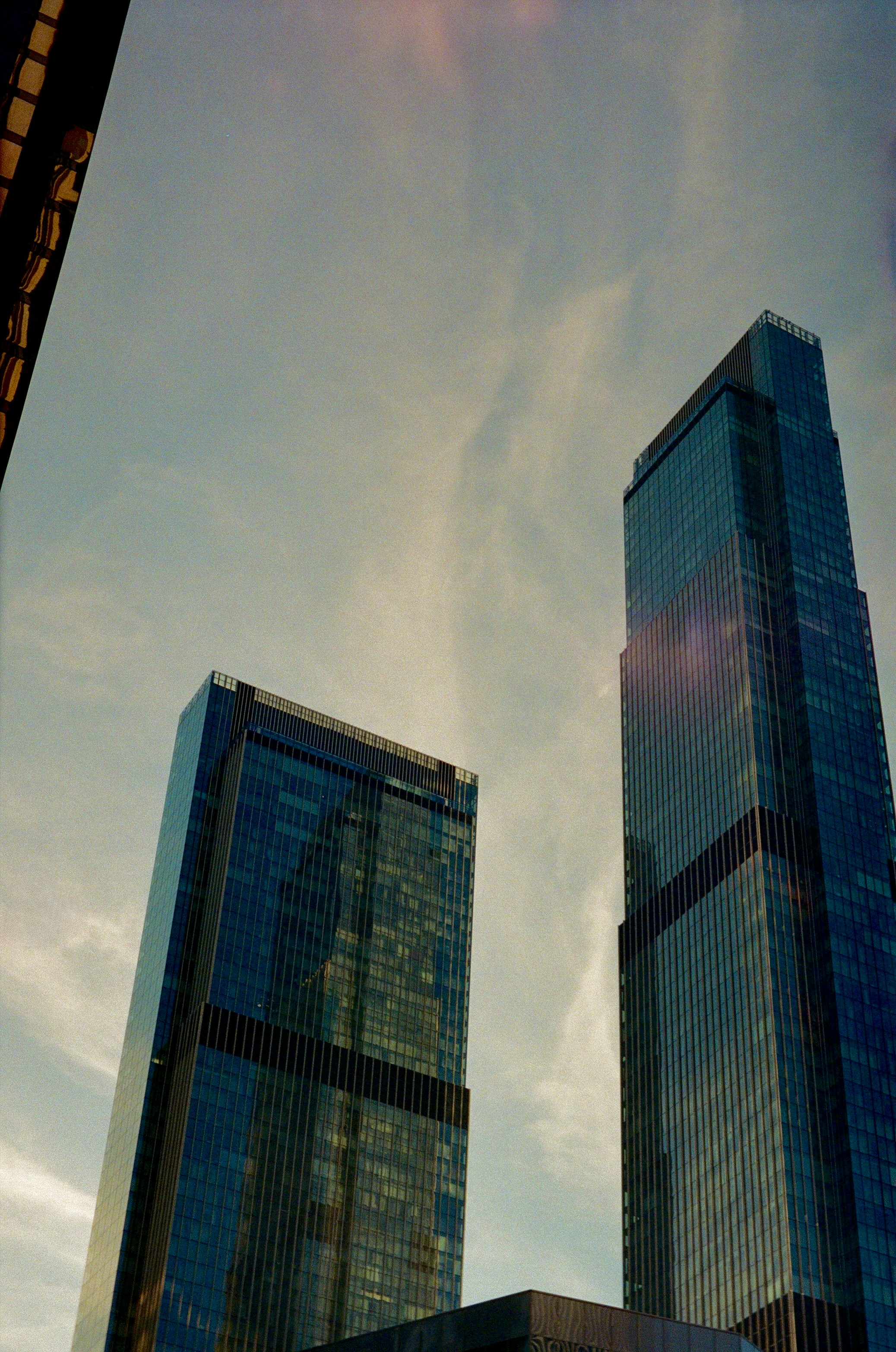 Skyscraper Echoes: Twin Glass Giants Reaching for a Clouded Sky
