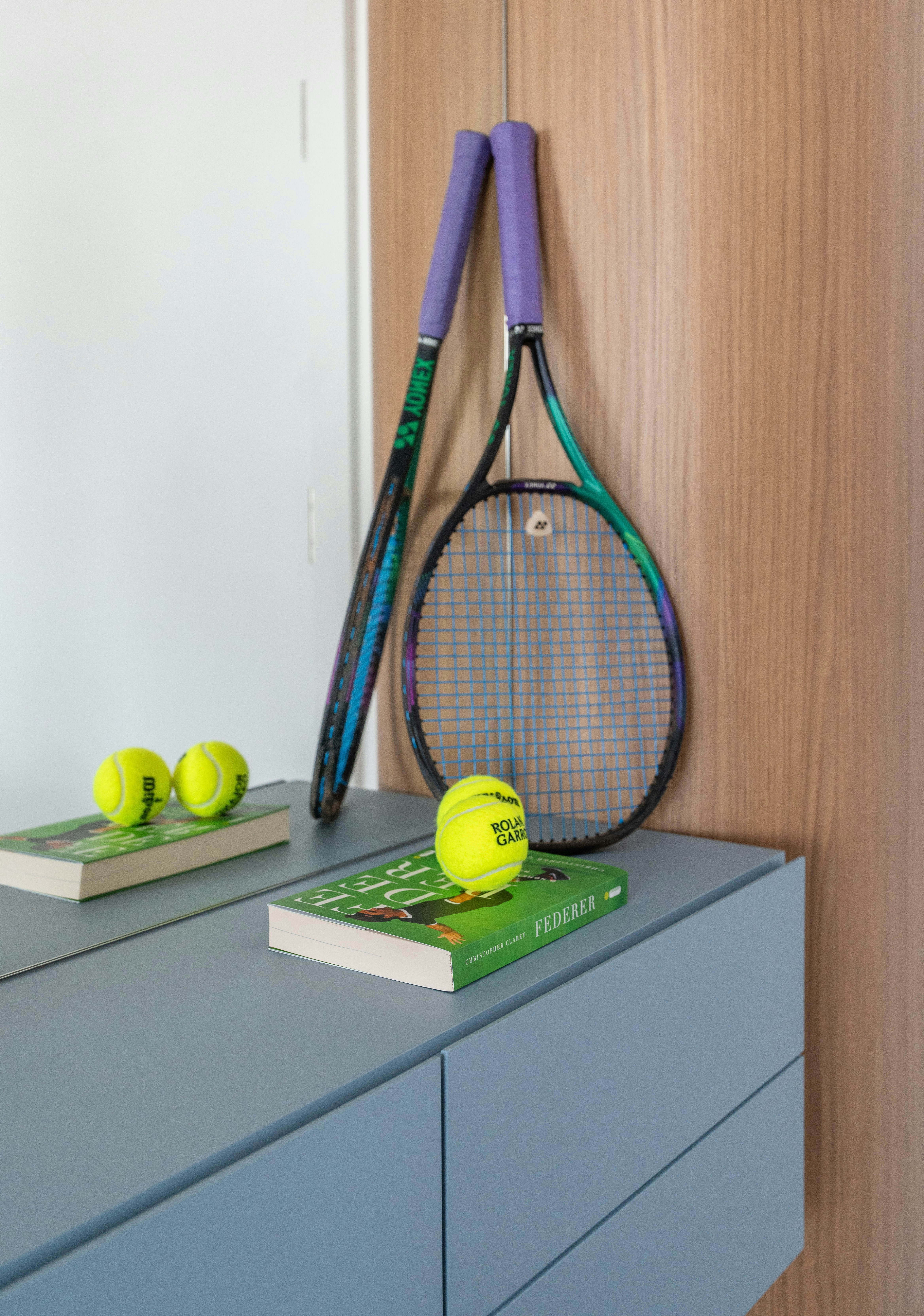 Tennis gear on a cedar cabinet: a still life of rackets, balls and books