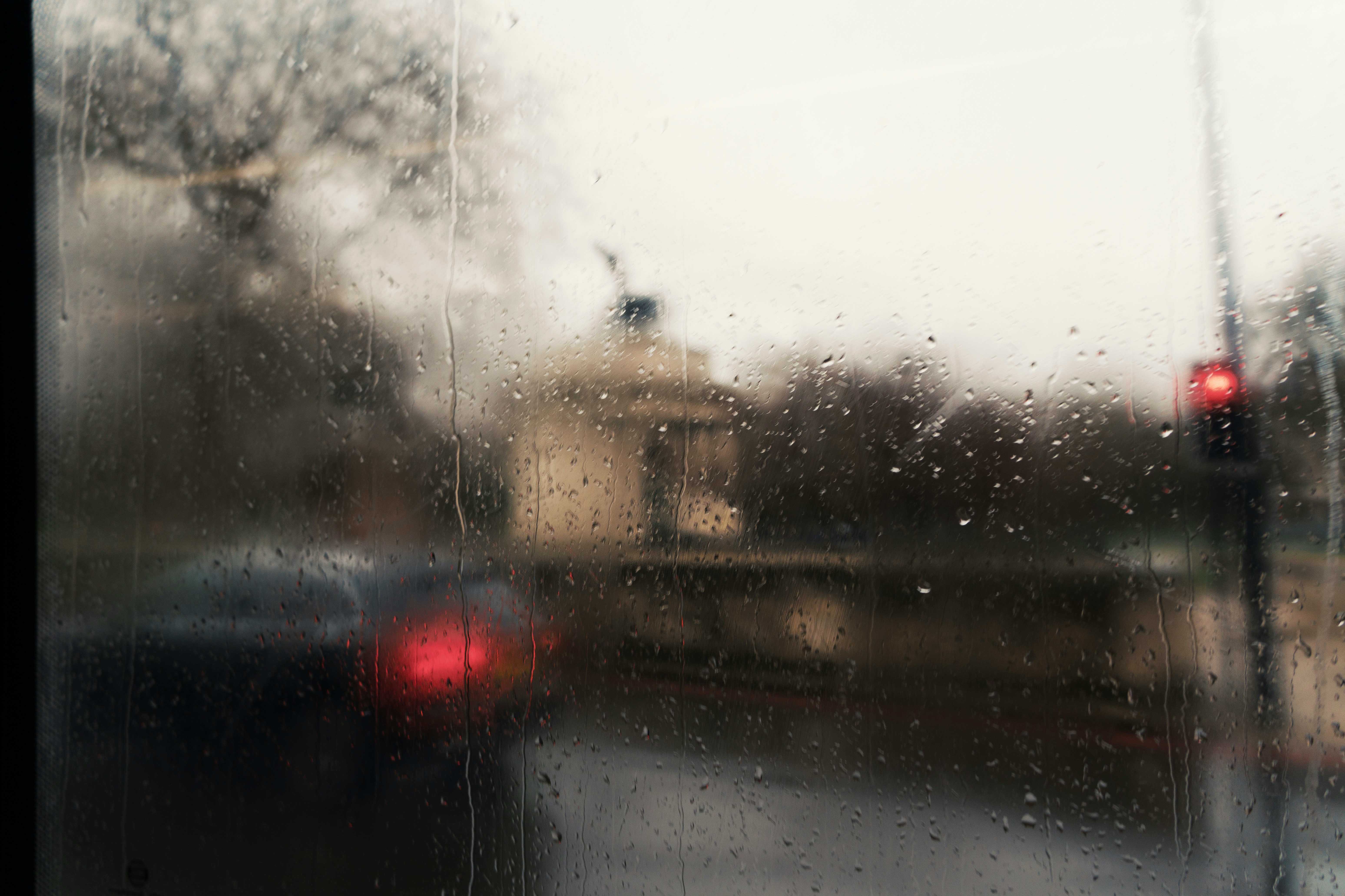 Rain-streaked window with a dim cityscape on the horizon