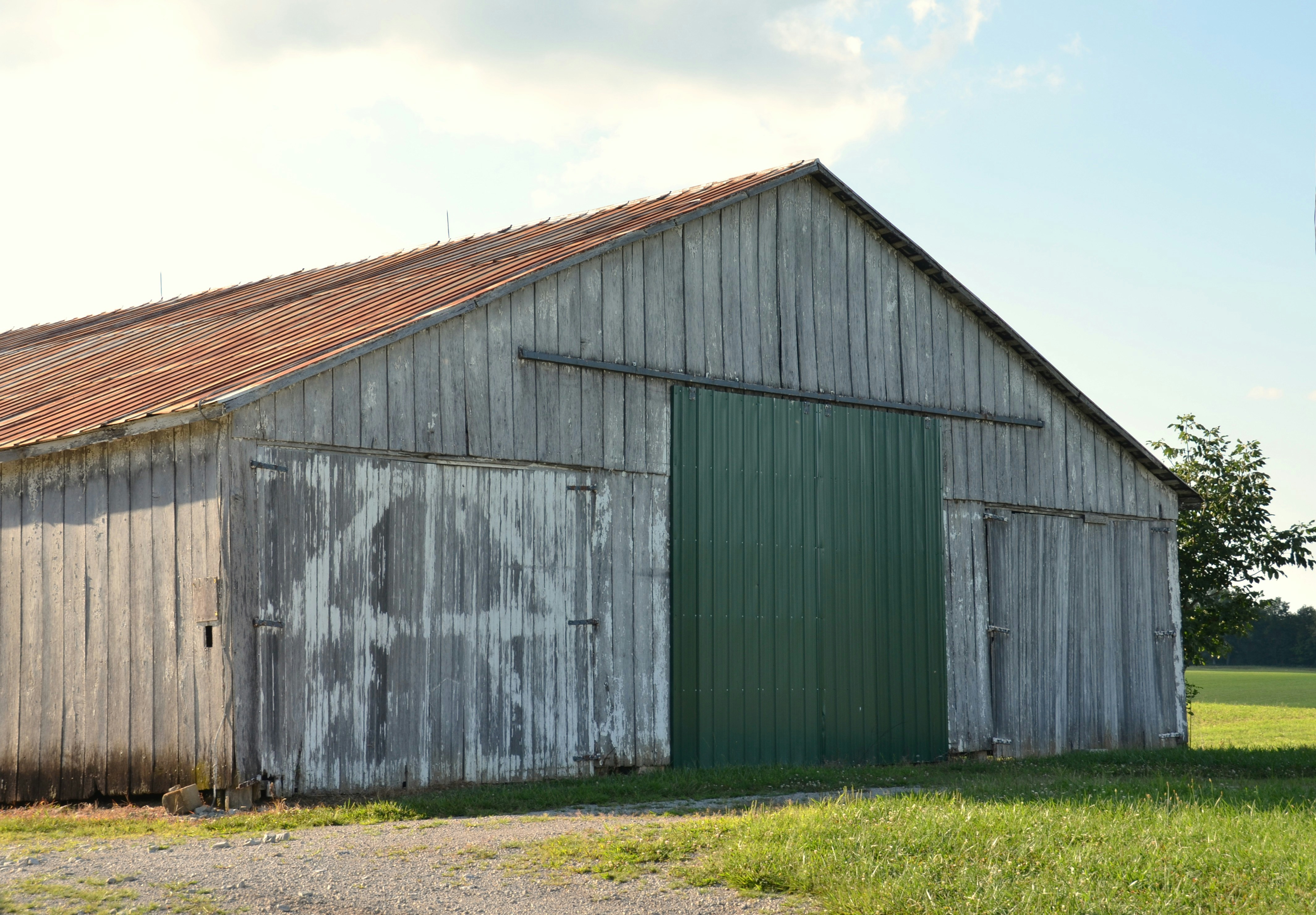 Weathered barn with a lone green door under a red roof