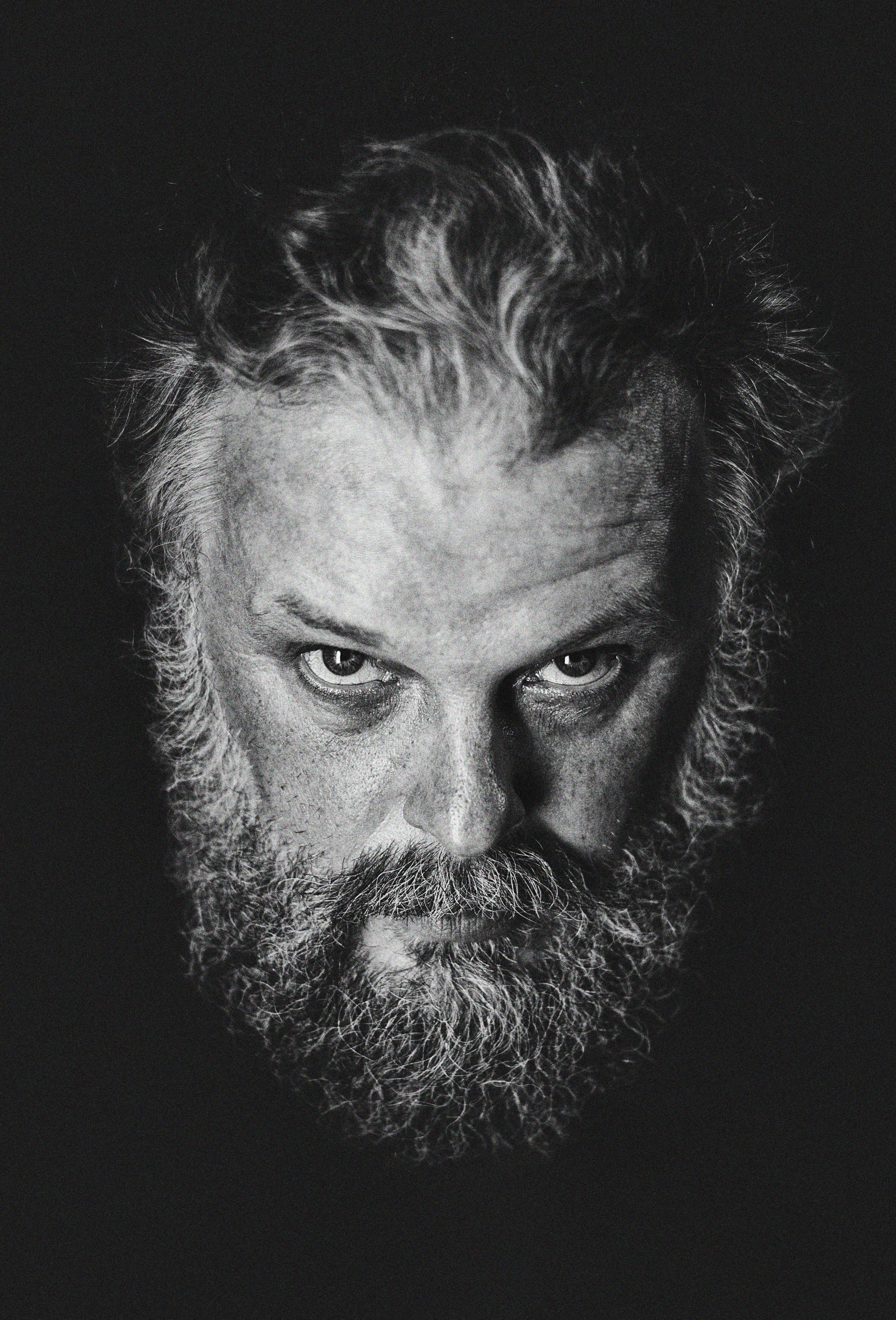 Intense Gaze: A Bearded Portrait Emerging from Darkness