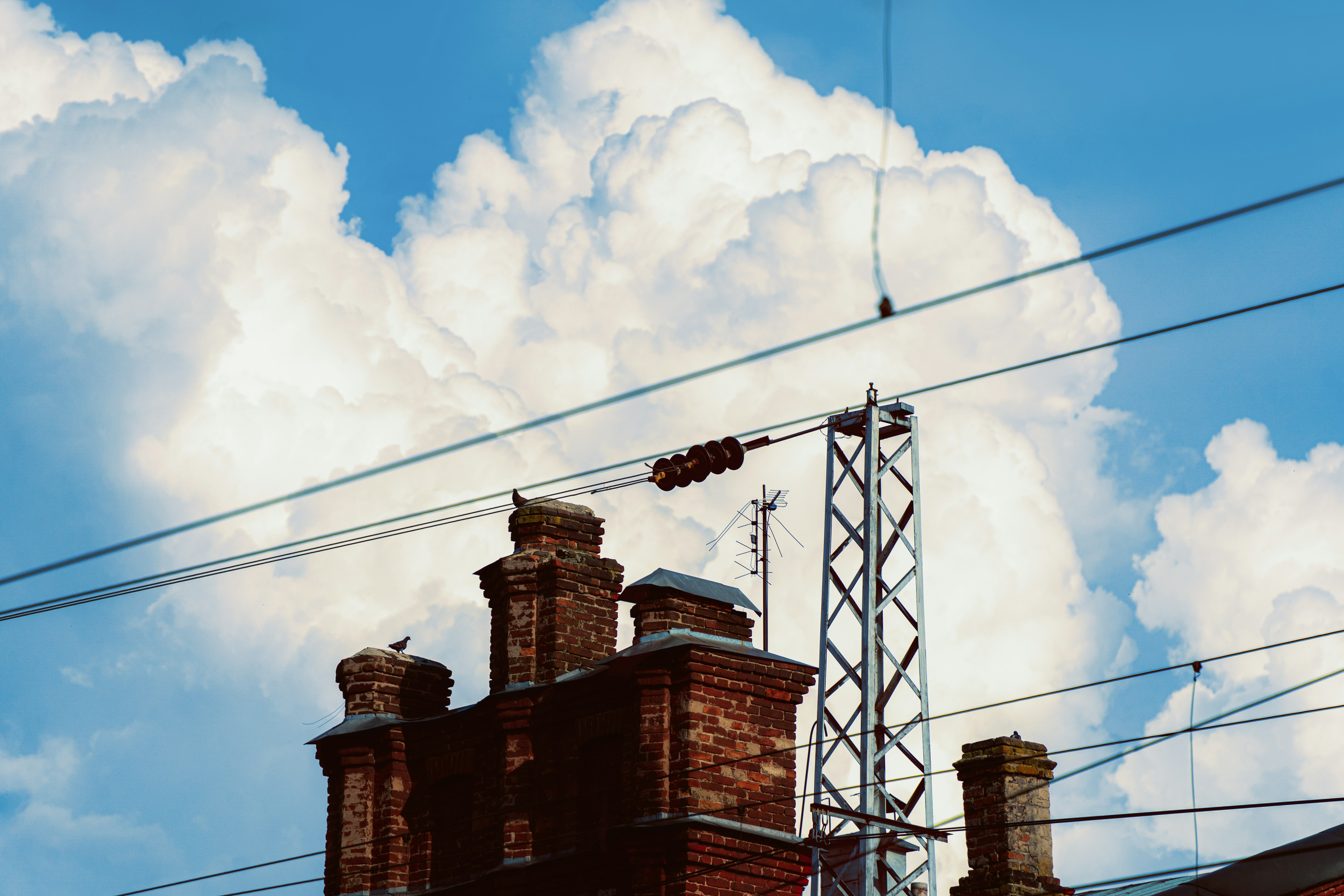 Brick Chimneys Under Electric Wirding Against a Brave Blue Sky