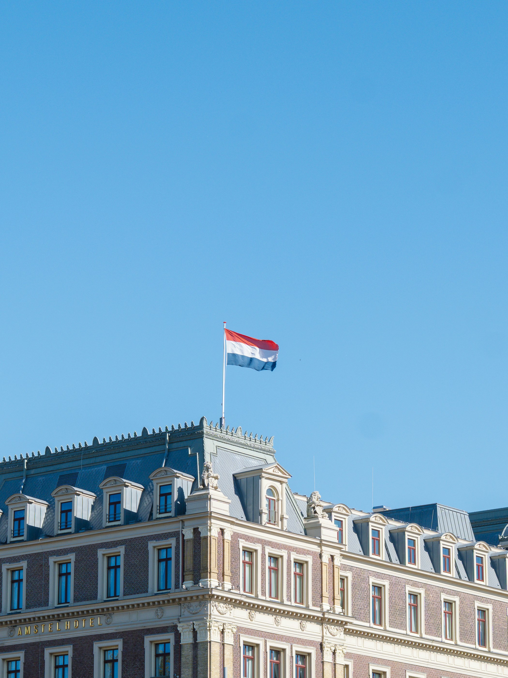 Flag Over Classical Facade: A Dutch Flag Graces a Corner Building