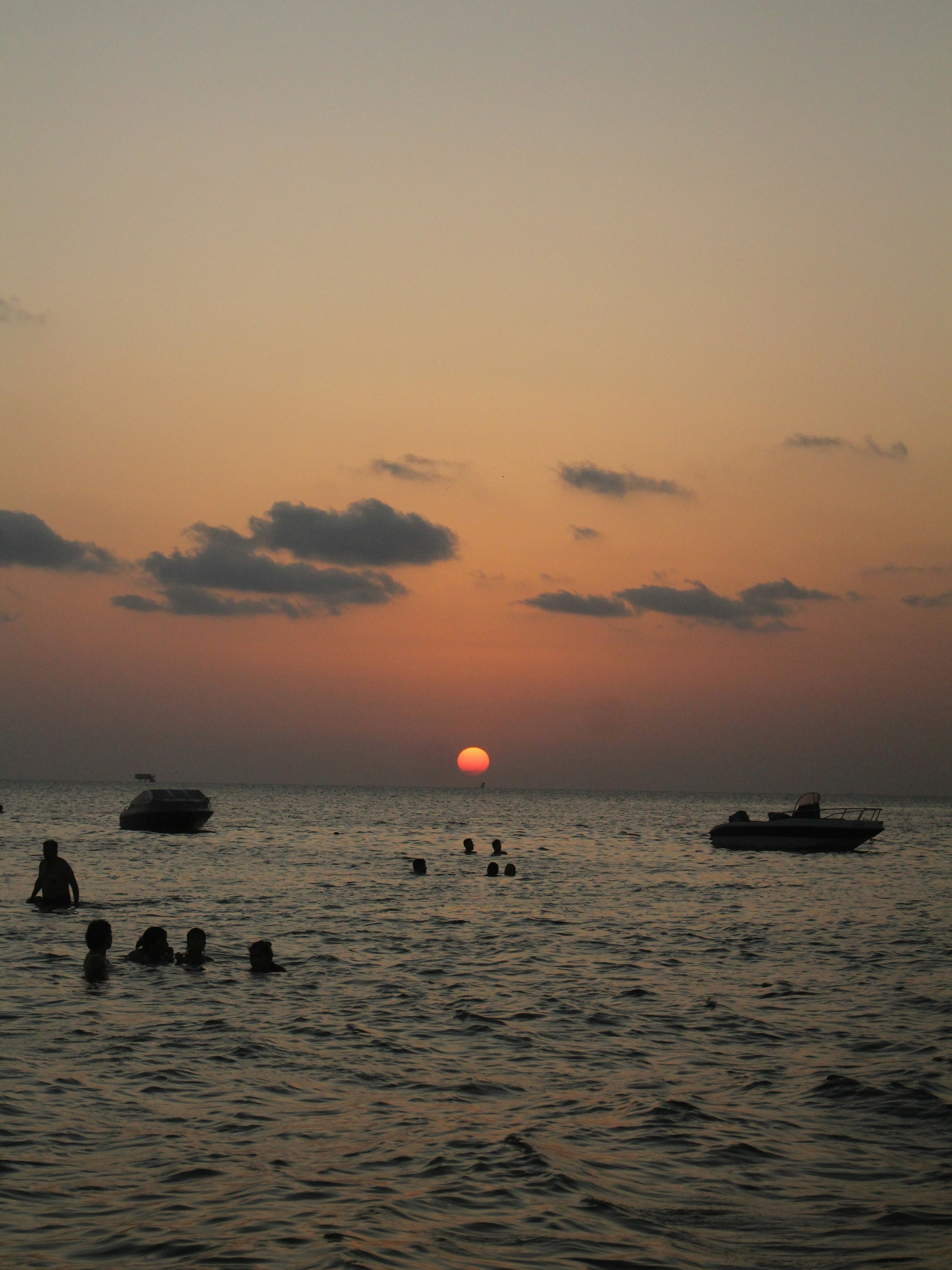 Sunset Over Gentle Waves: Boats Silhouetted at Dusk