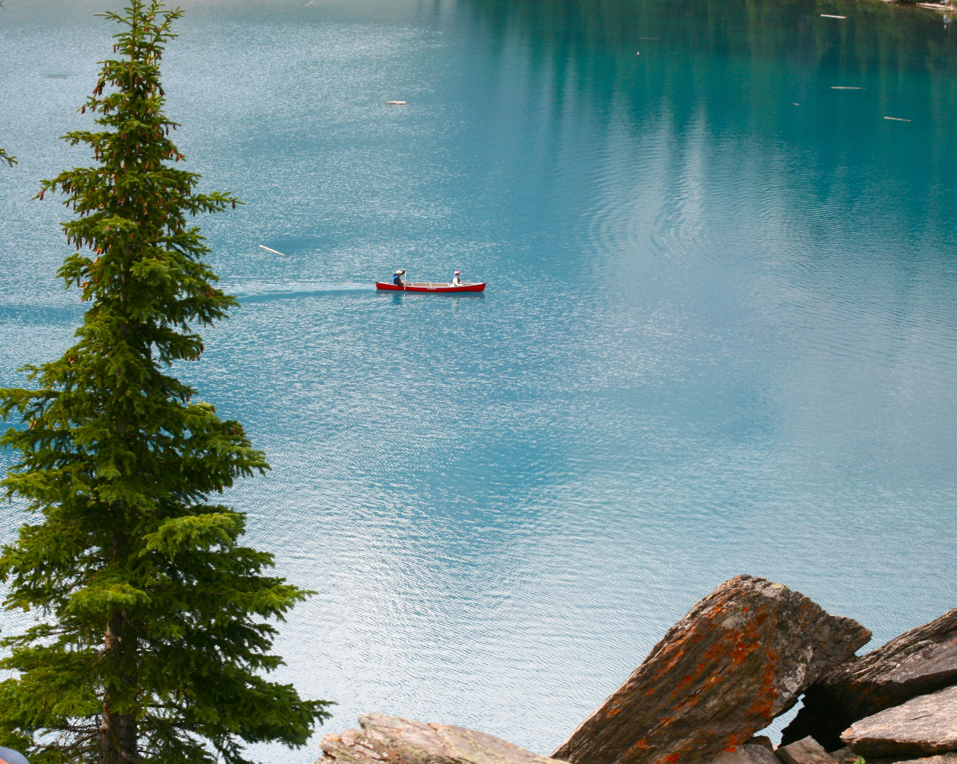 A Lone Red Boat Drifts Across Turquoise Alpine Waters