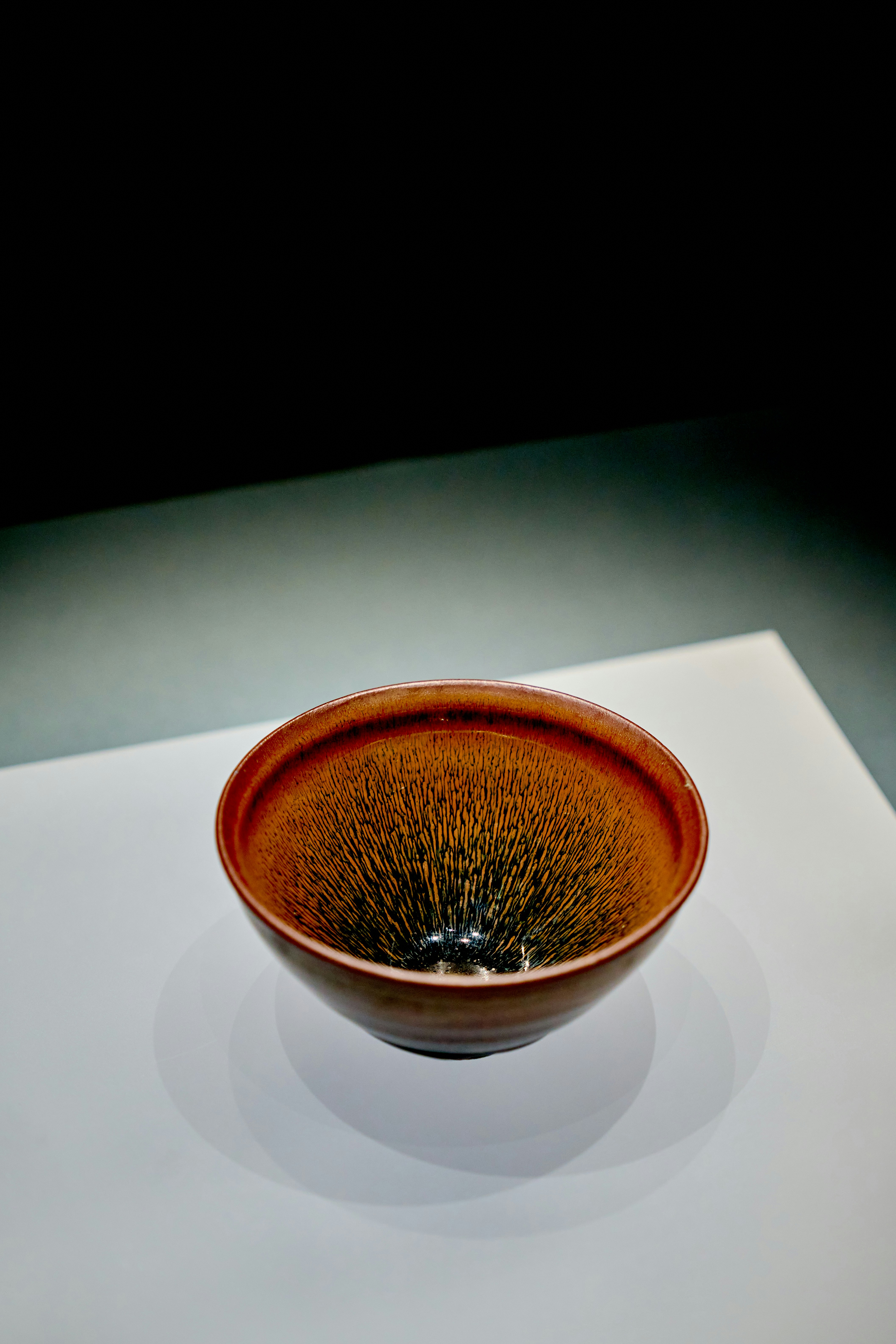 Minimal Still Life: A Ceramic Bowl on White Sheet under Soft Spotlight