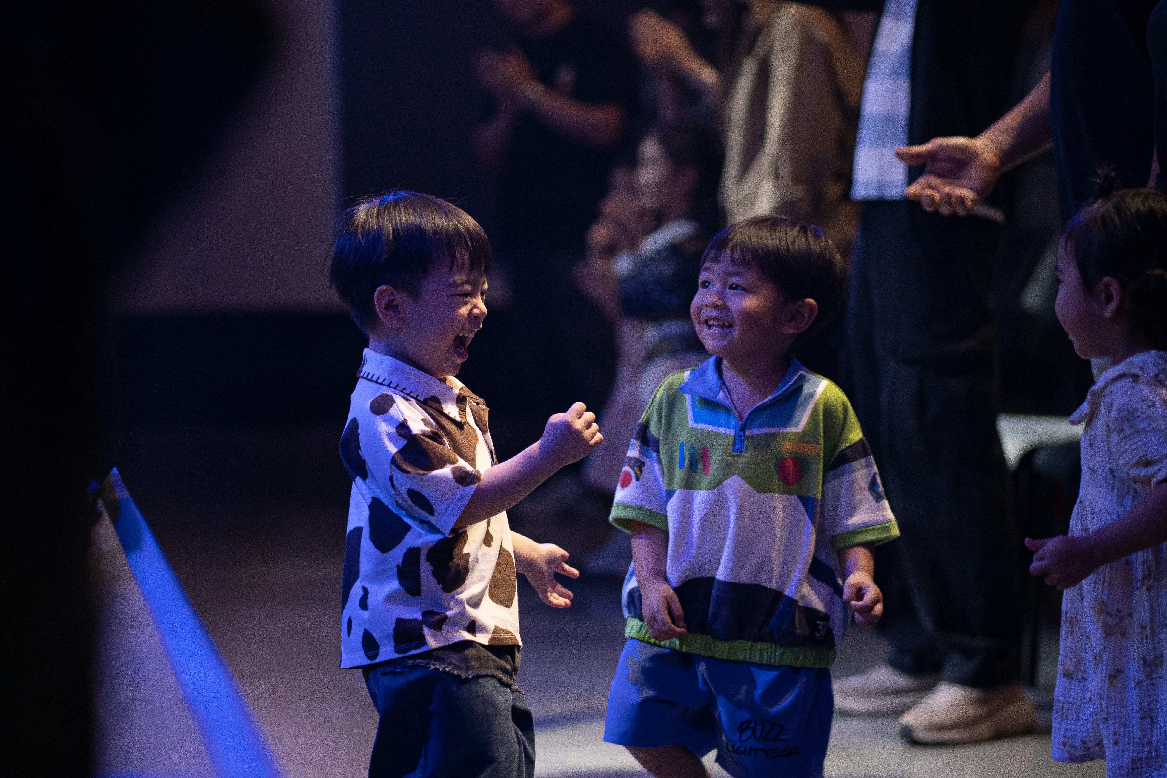 Joyful exchange: two boys sharing a moment on the dimly lit stage