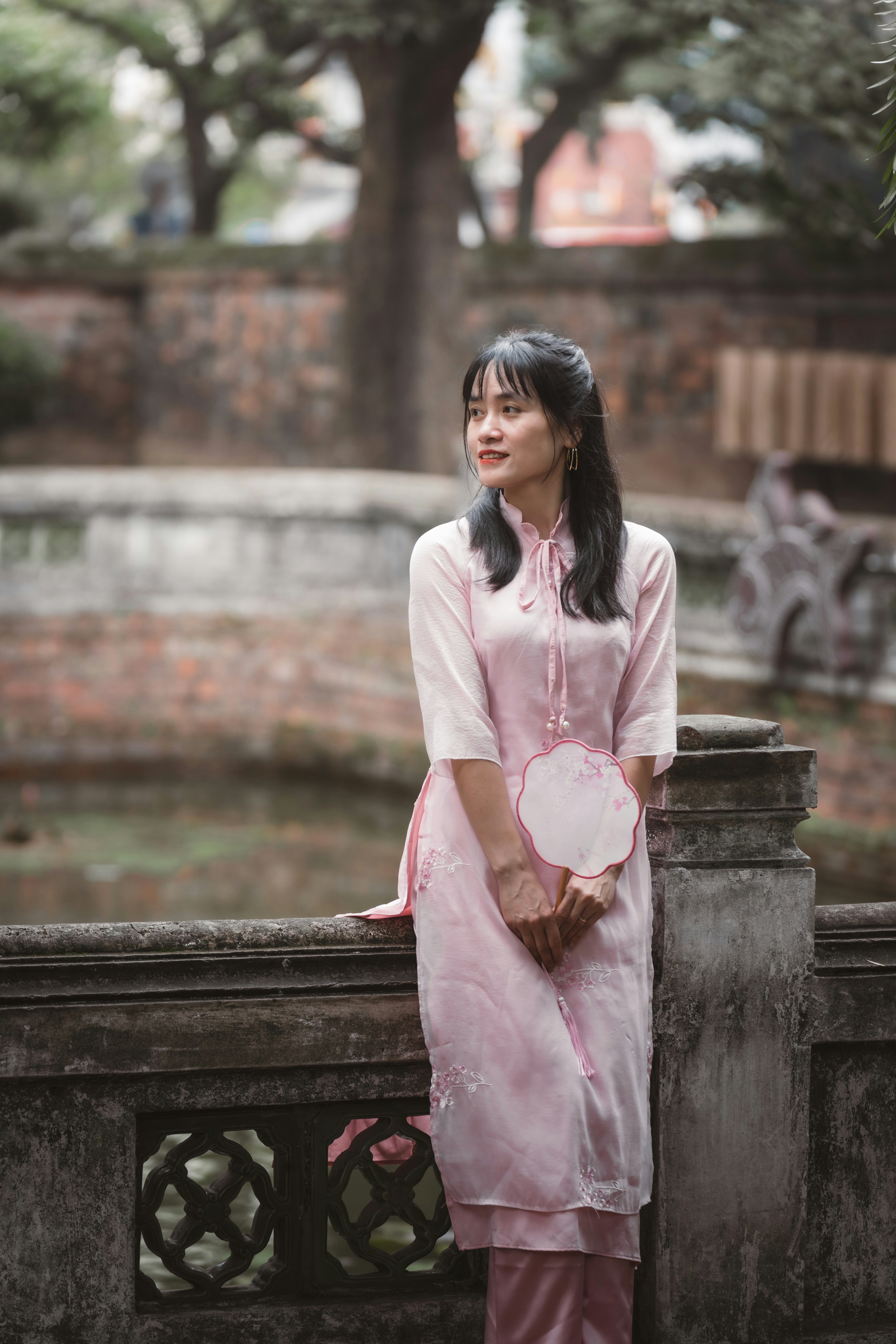 Pink Ao dai by the pond: quiet poise amid ancient bricks