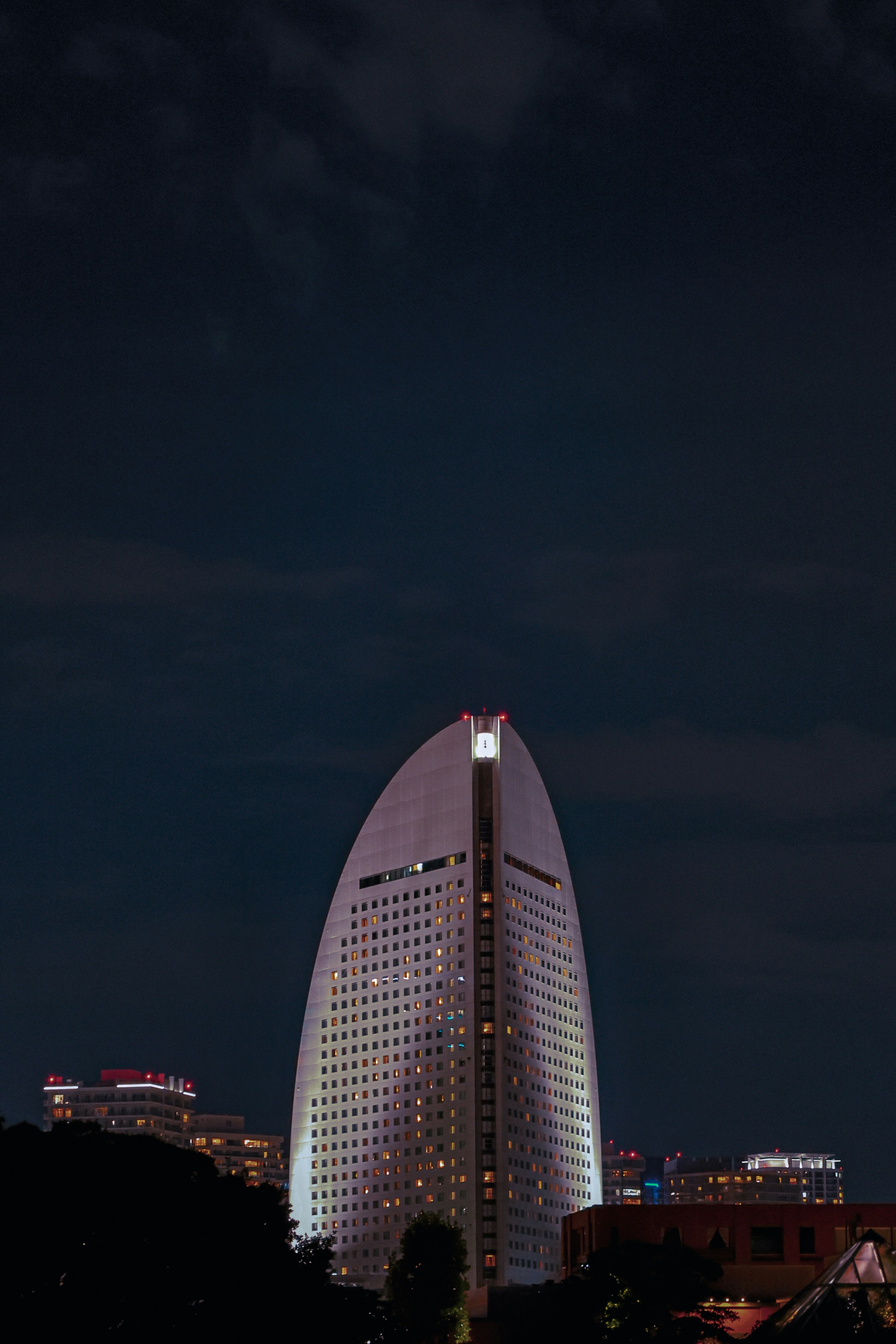 Night Capsule: The Arched Skyscraper Rising Above the Quiet City