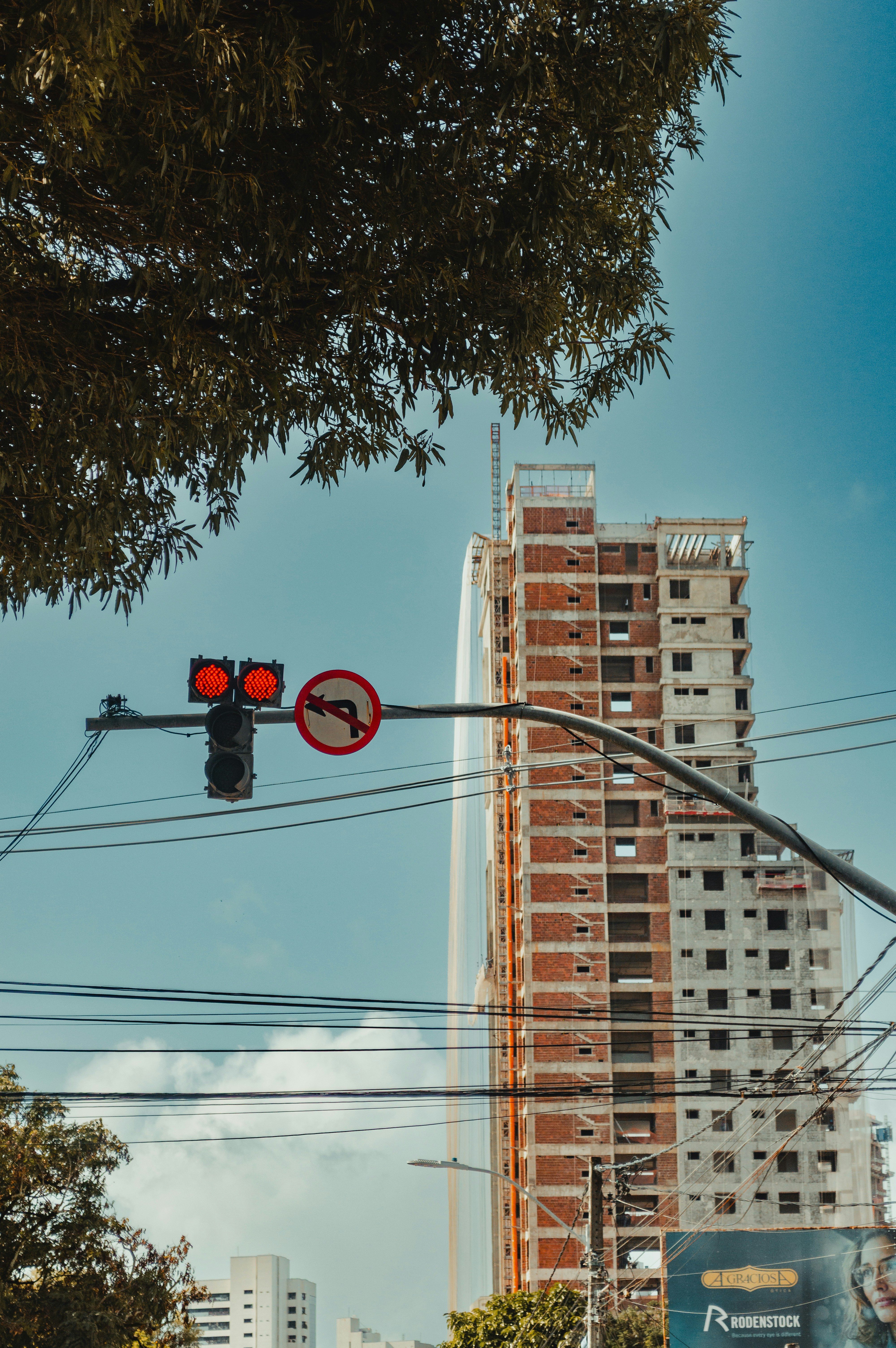 Urban Skeleton Rising: A Red-Coded Traffic Signal Framed by Tower Under Construction