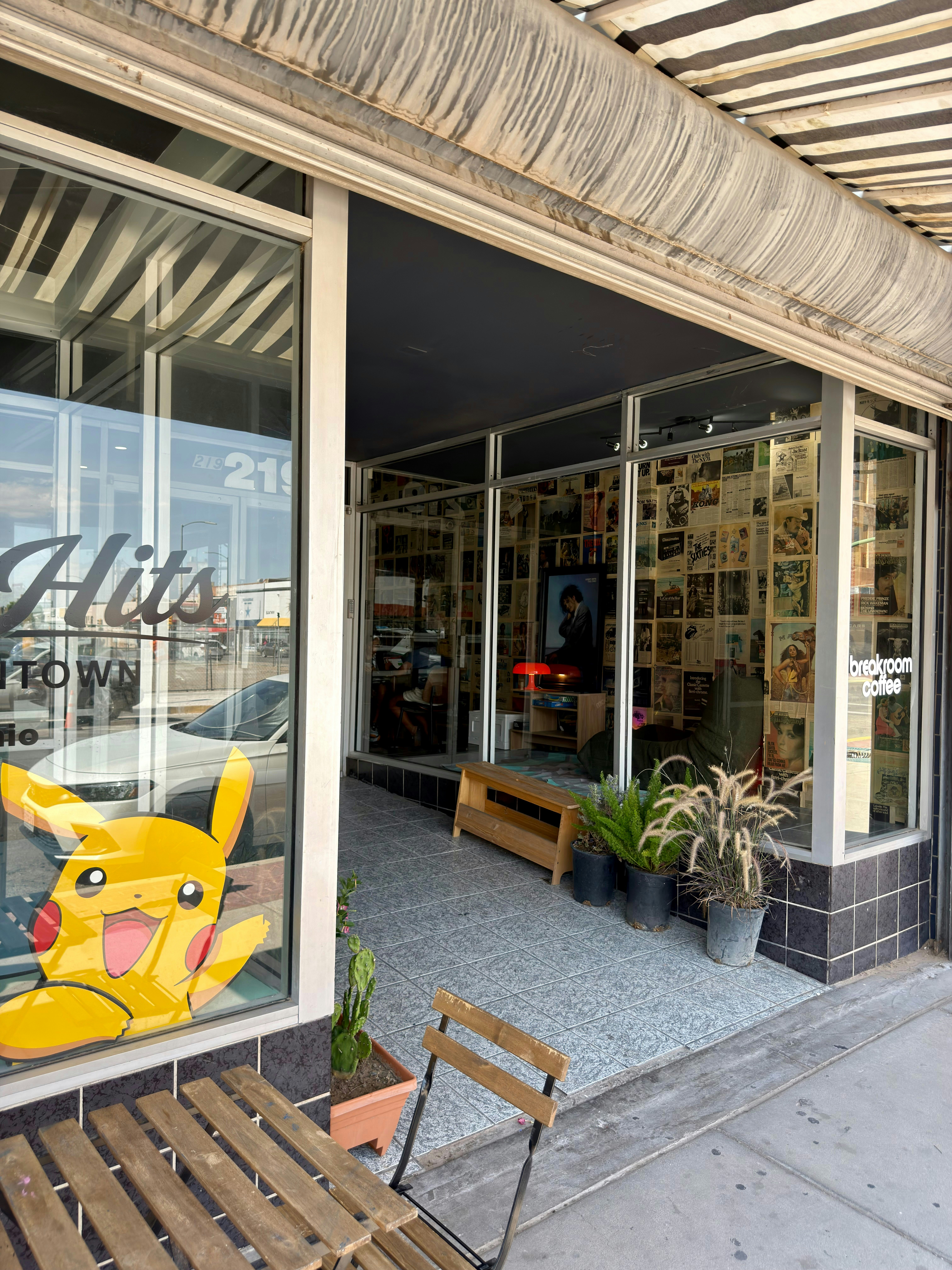 Sunlit storefront with Pikachu mural and cozy courtyard seating