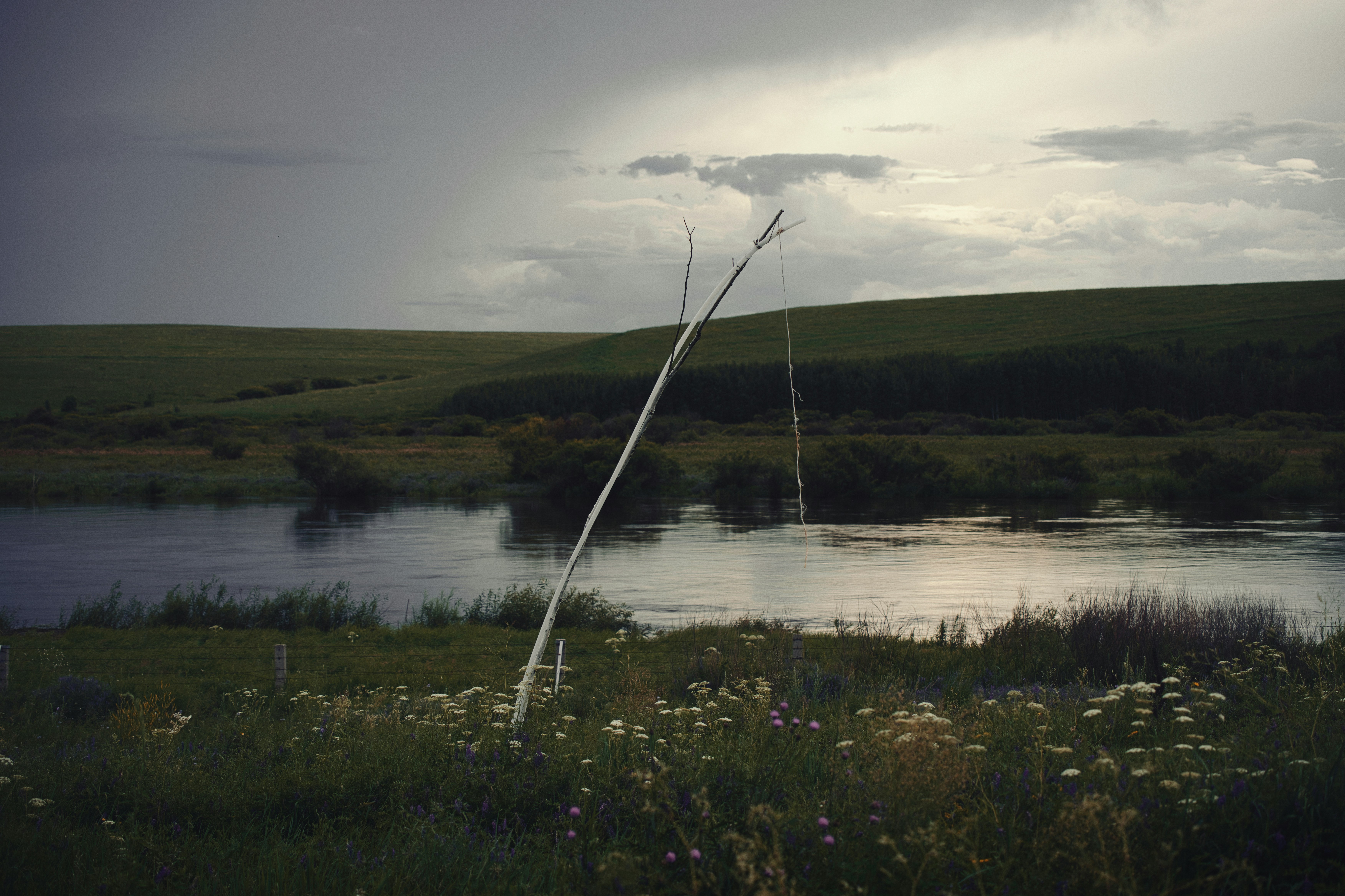 Broken staff by the river: a stormwatch scene across the marsh