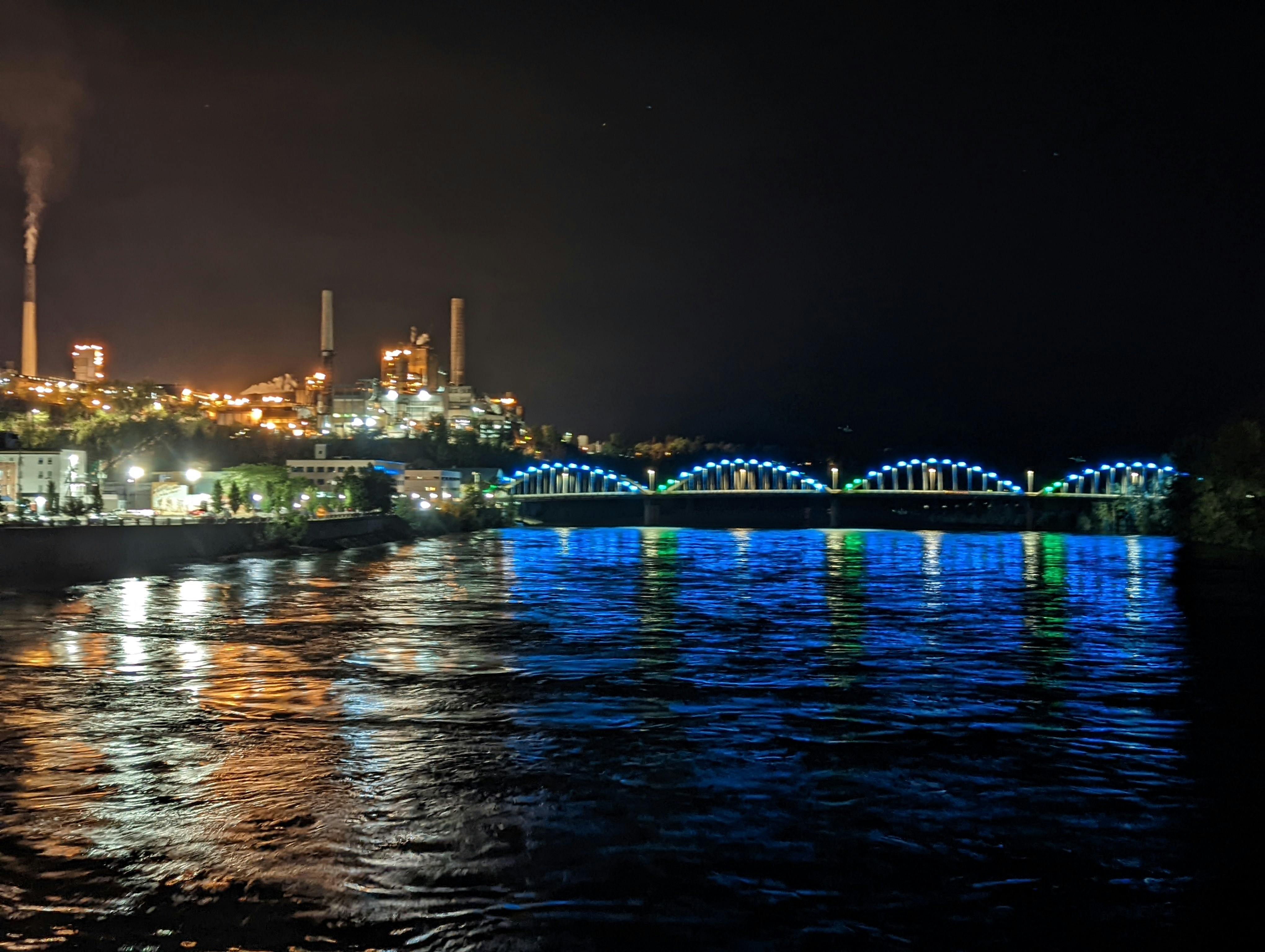 Neon Reflections: Nighttime Industry and Bridge over a City River