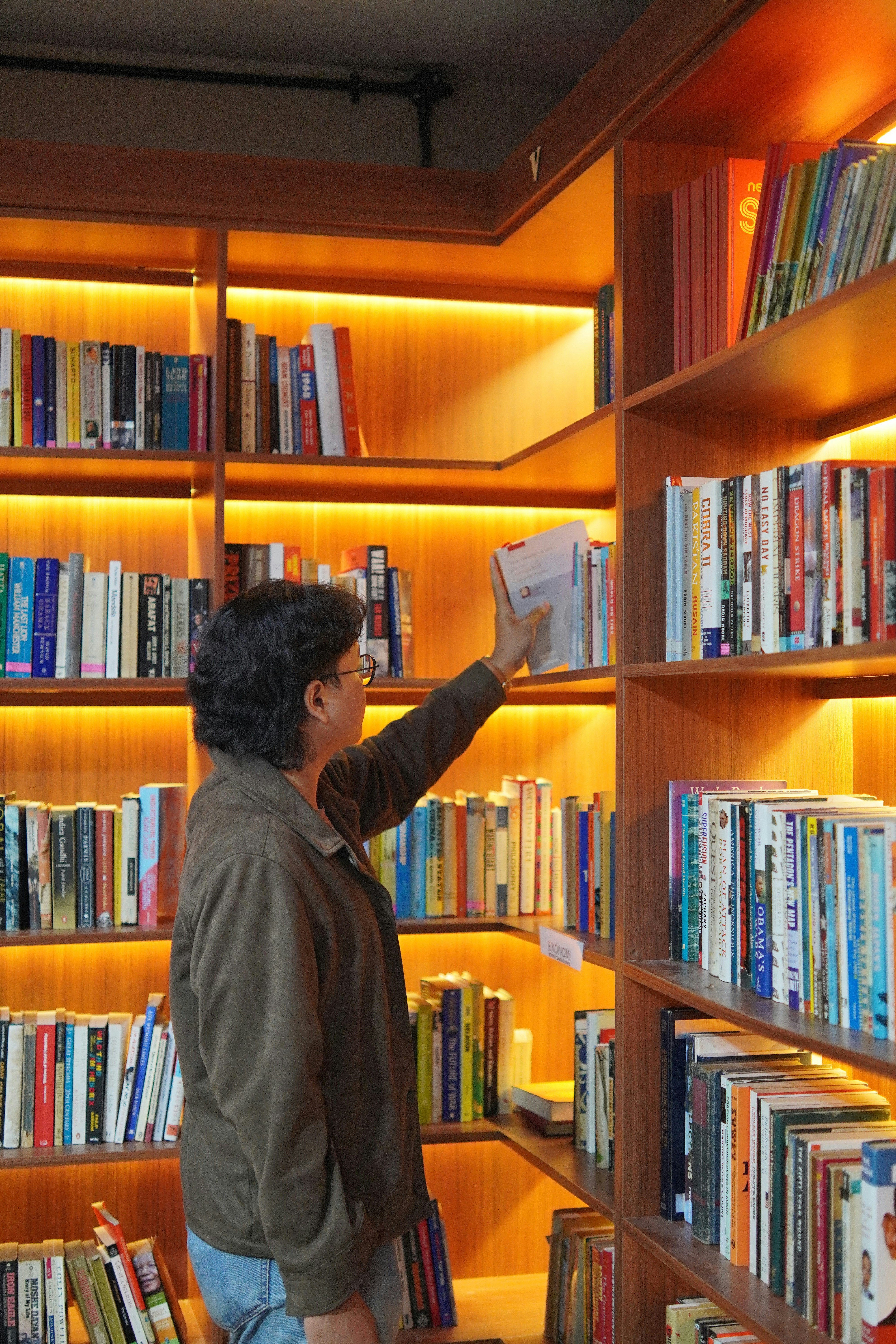 Librarian in Amber Shelves Reaches for a Book