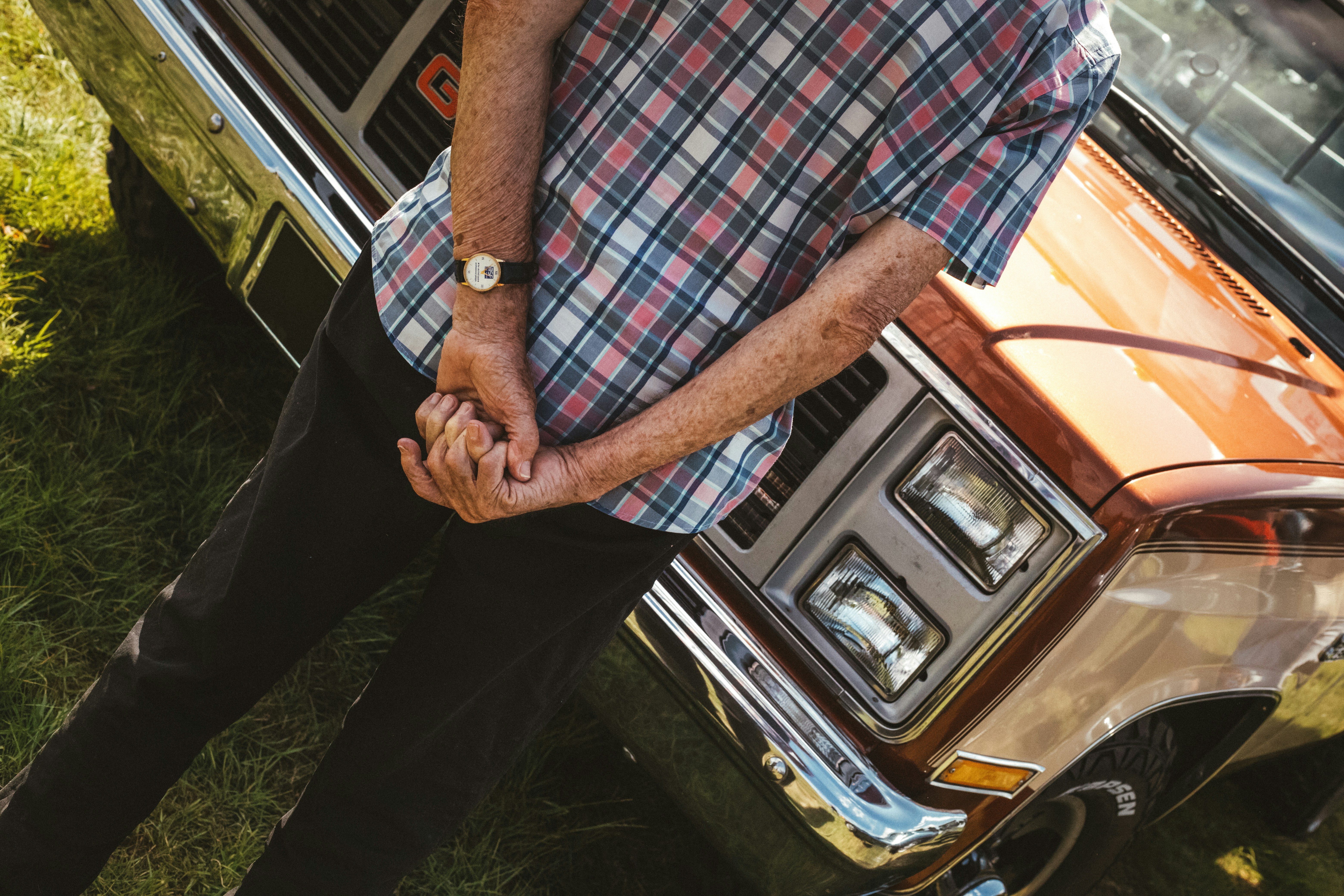 Hands in Moment: A Plaid-Clad Presence by the Classic Grille